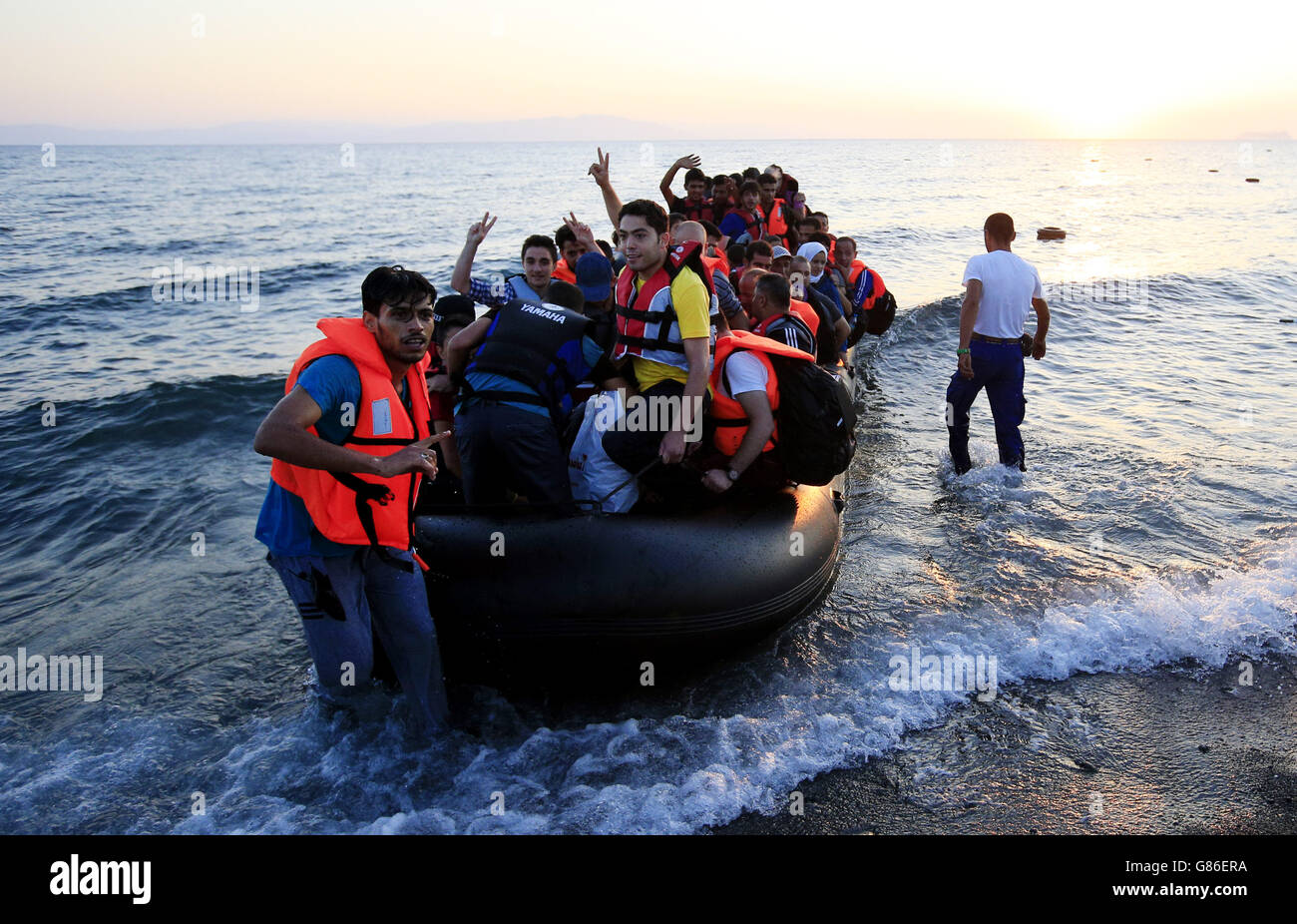 Migrants and refugees in a rubber dinghy arrive on the beach at Psalidi ...
