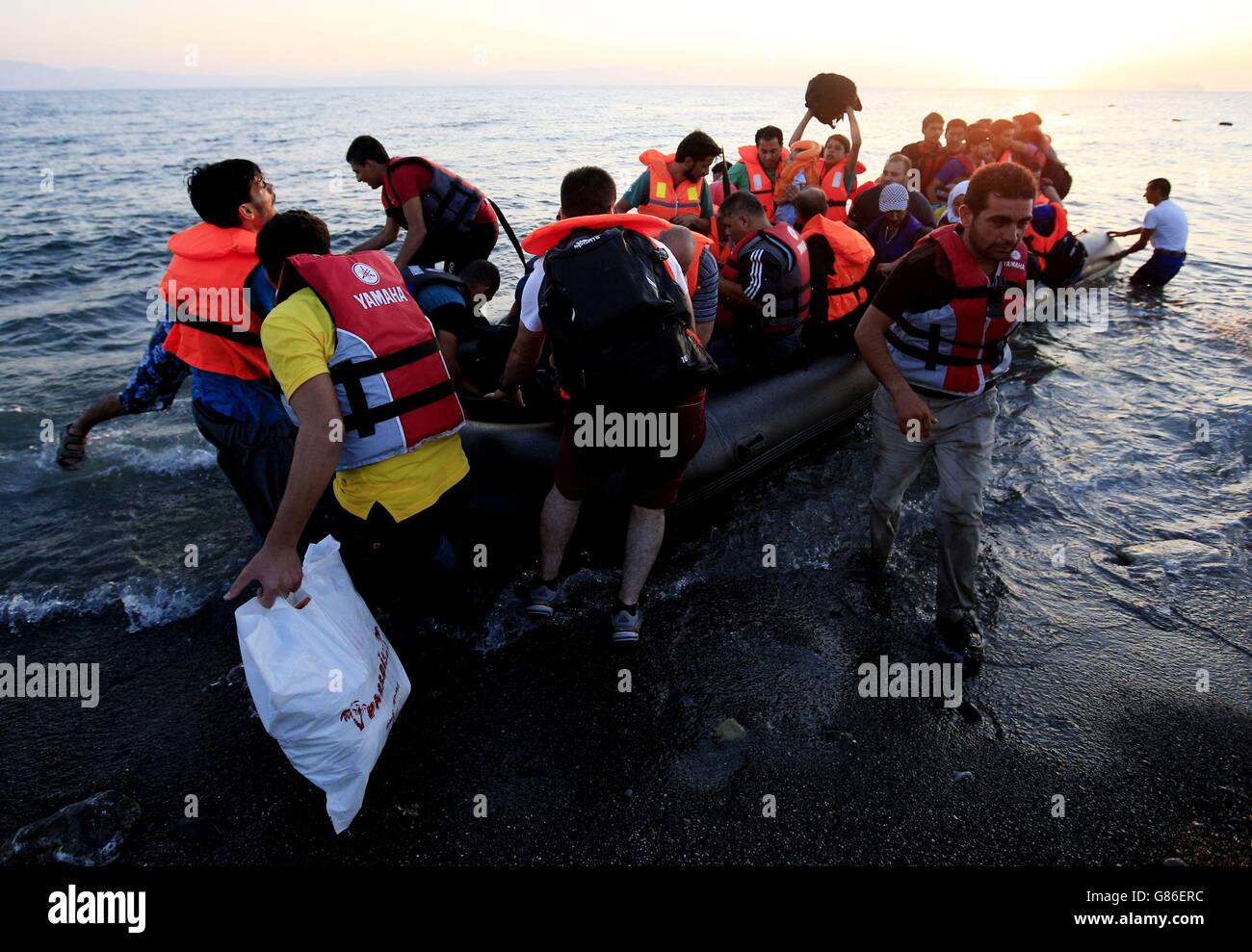 Migrants and refugees in a rubber dinghy arrive on the beach at Psalidi ...