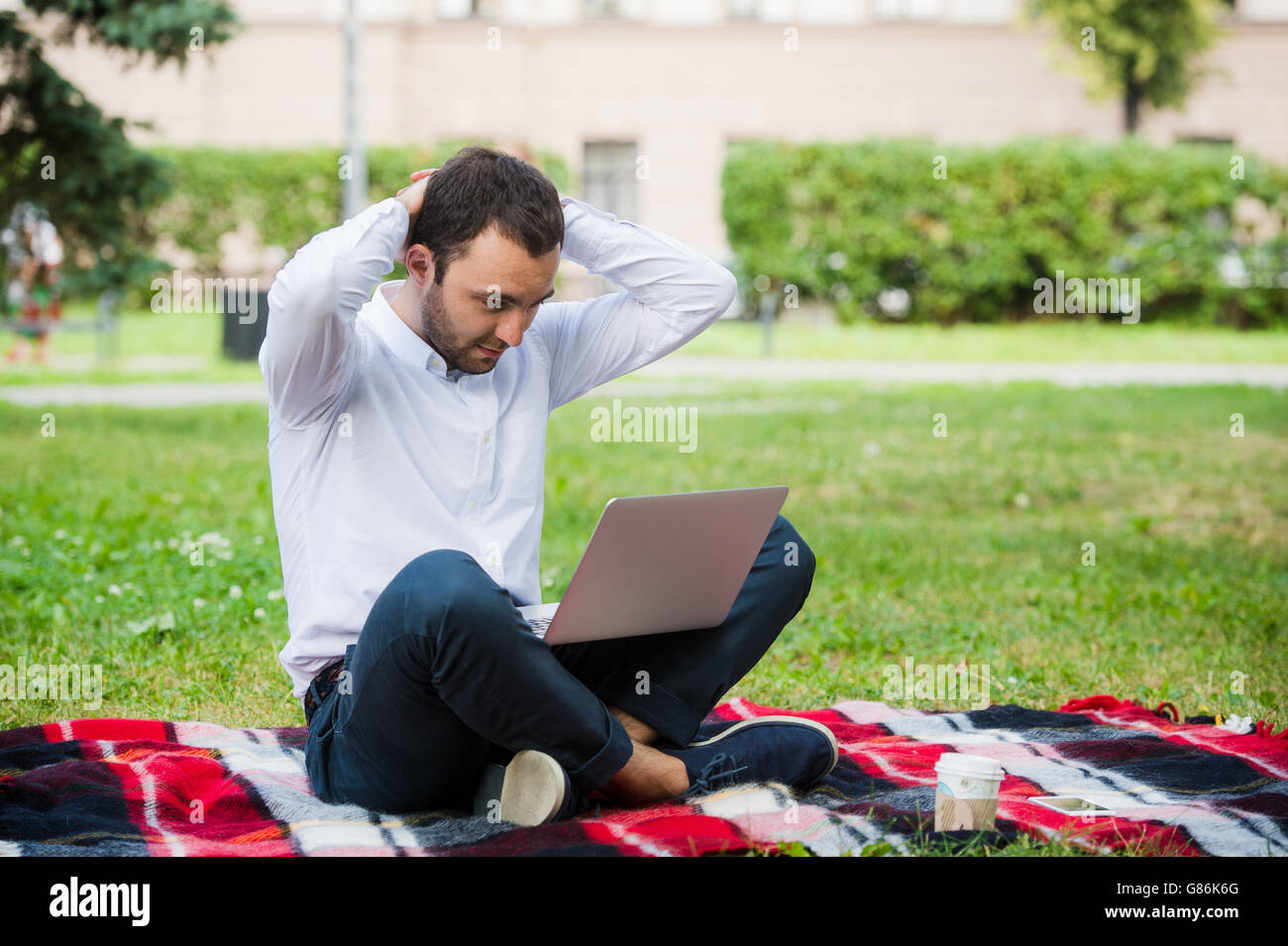 Man is working using laptop at park. Outdoor, guy look challenged and ...