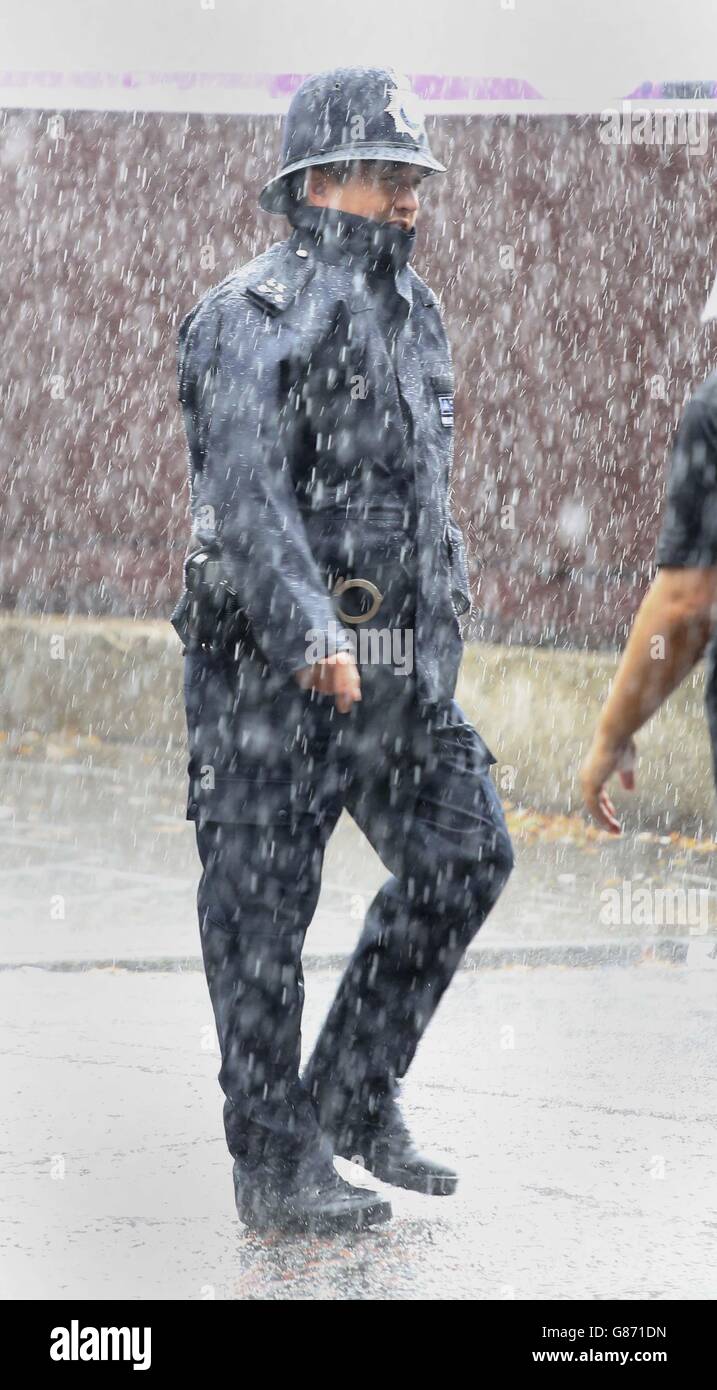 A police officer walking in a heavy rain outside the Shell London HQ ...
