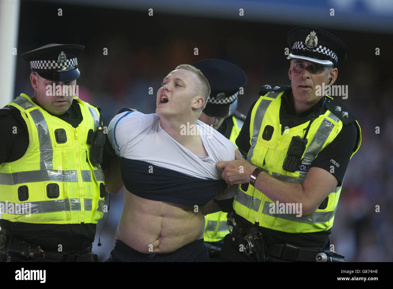 A Rangers fan is taken away by the police after invading the pitch ...
