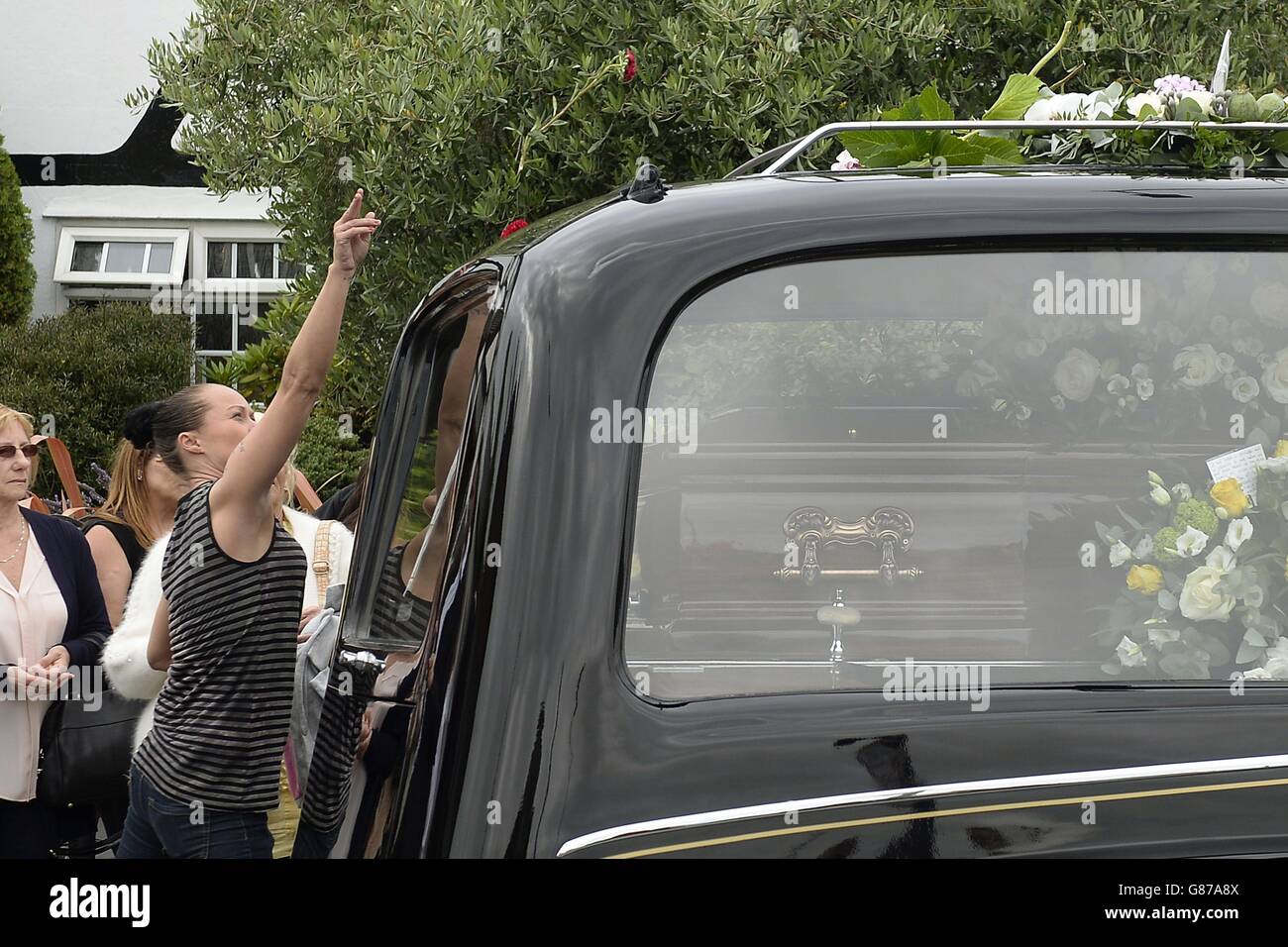 A woman throws a red rose onto the coffin of Cilla Black as it makes ...