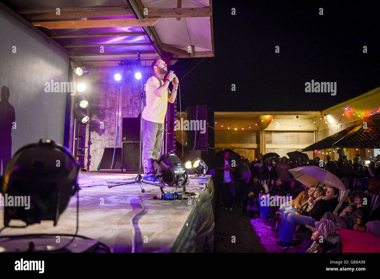 Crowds sit in the rain watching Adam Bloom perform during an evening of ...