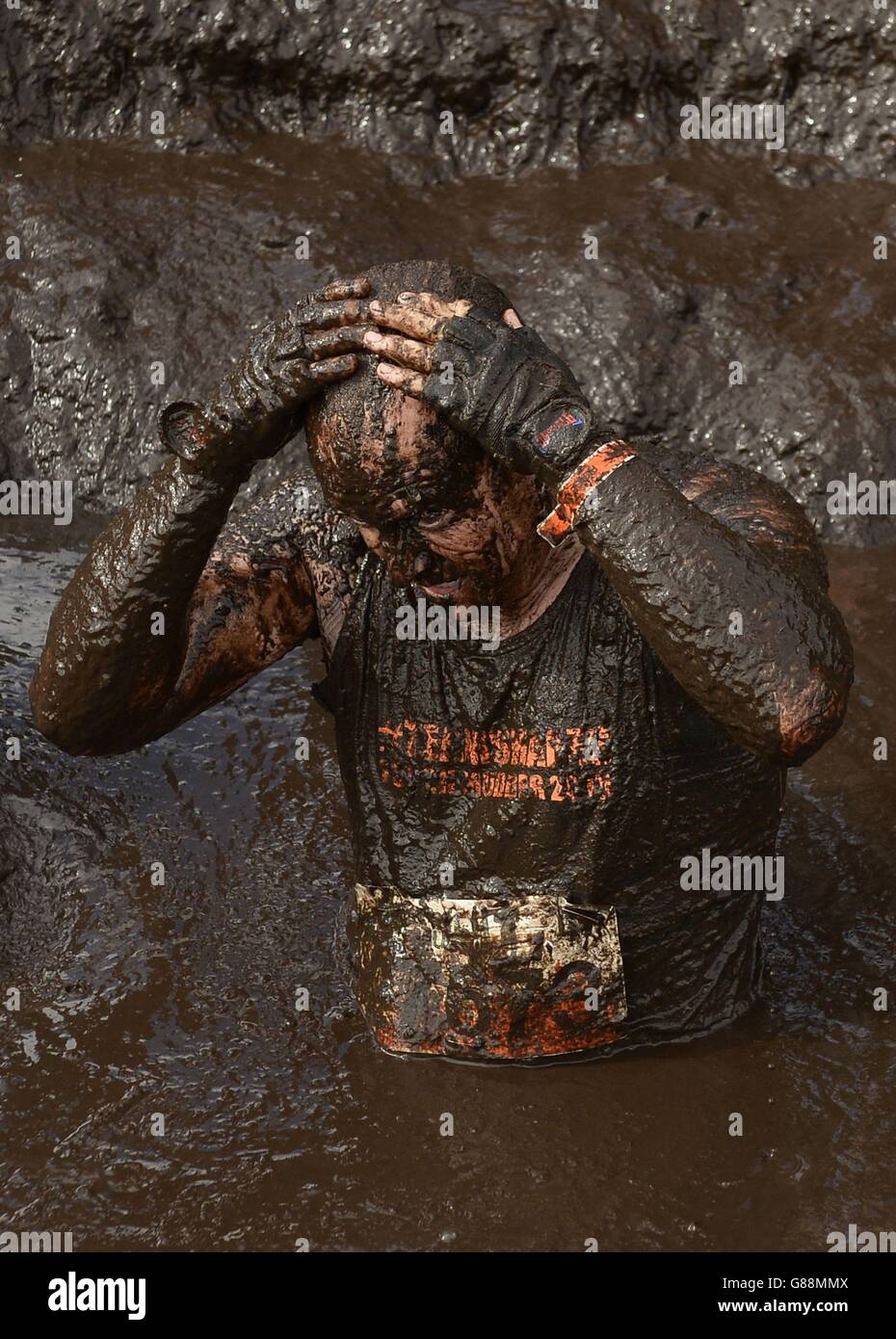 A participant wipes mud from his head during Tough Mudder North West at ...