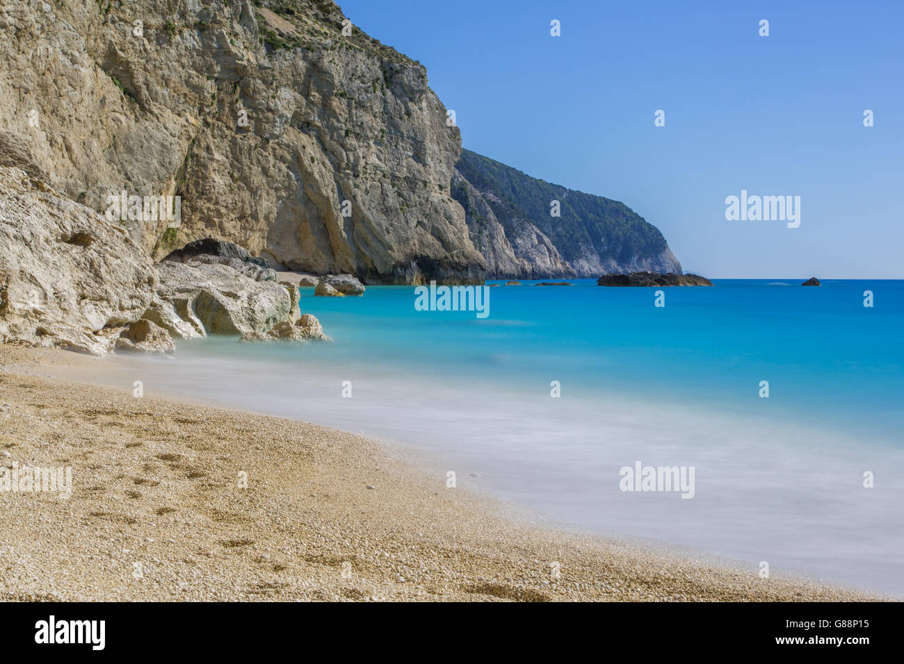 Sand beach with blue sea, blue sky and rocks Stock Photo - Alamy