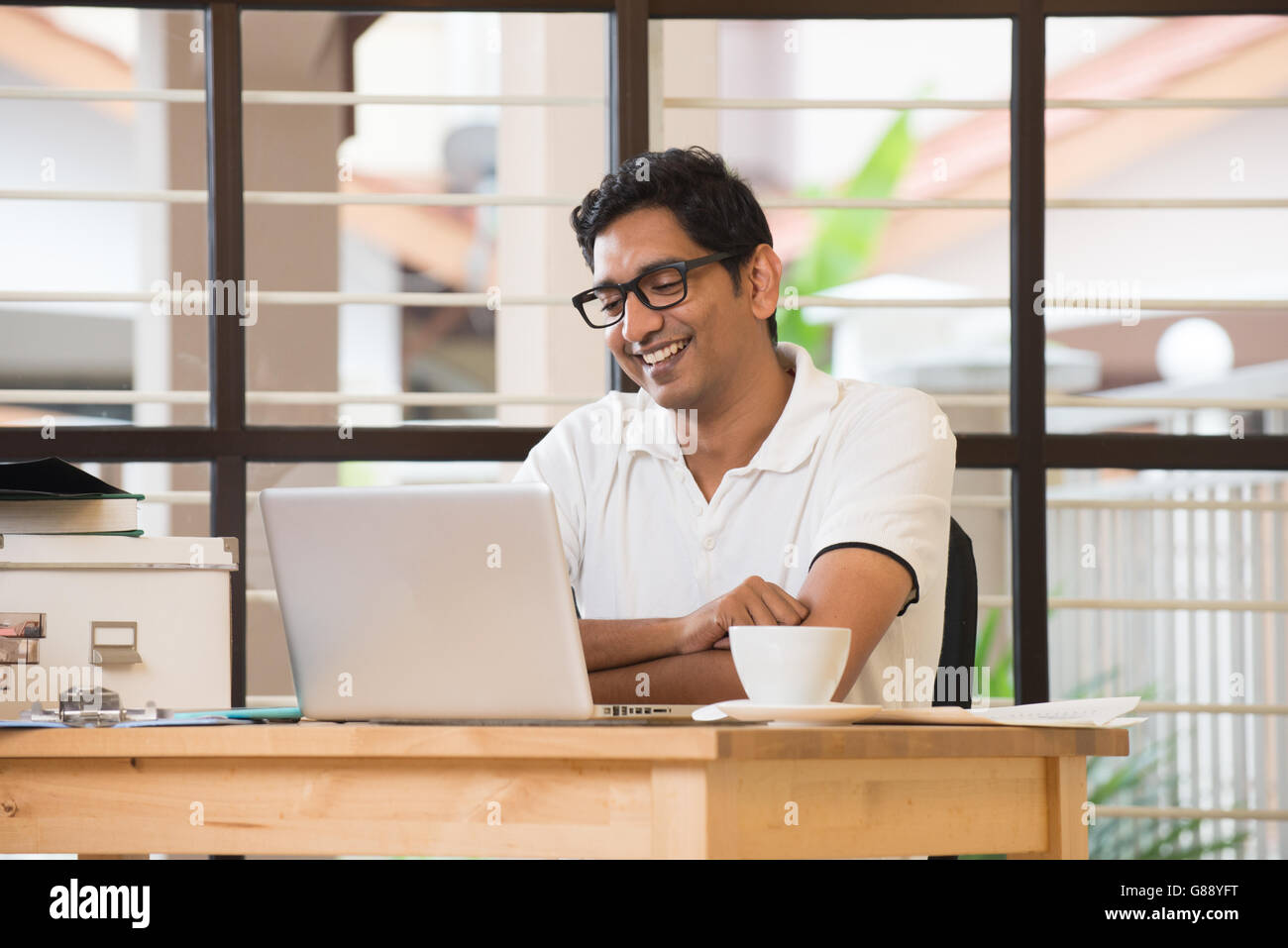 casual indian man smiling and working at office Stock Photo - Alamy