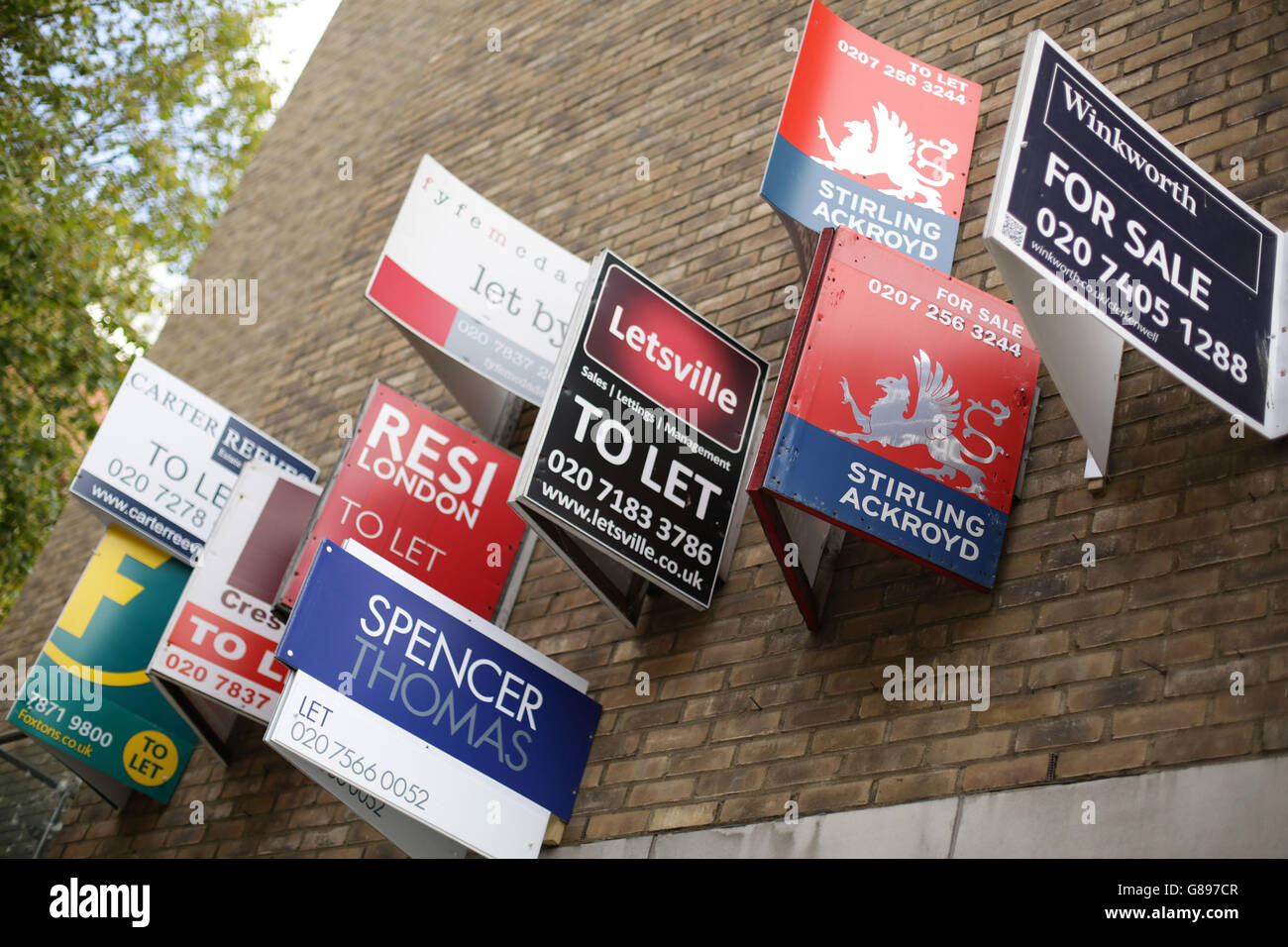 A row of For Sale, Let By and To Let estate agent signs on a wall in ...