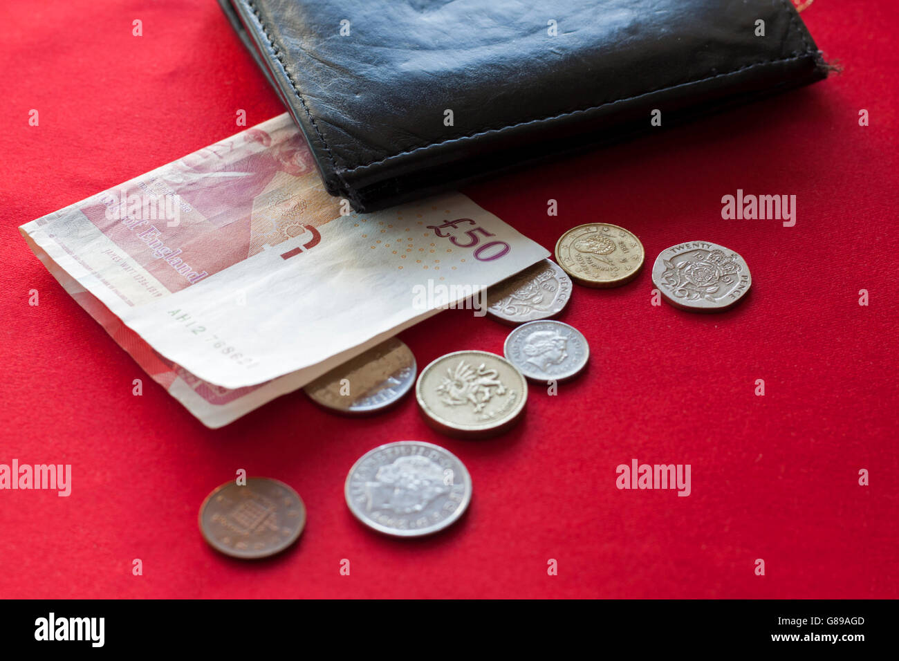 Folded British pounds and coins lying on red background with black ...