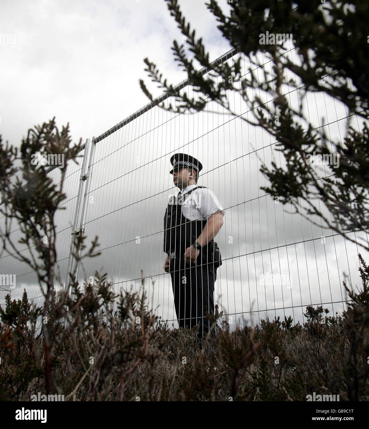 A police officer inspects the newly erected 5km perimeter fence ahead ...