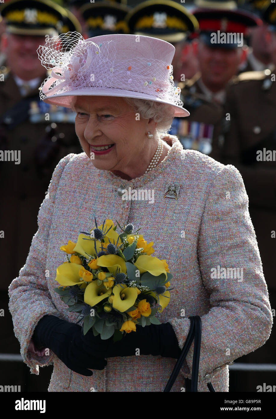 Queen Elizabeth II carries a bunch of flowers presented to her by two ...