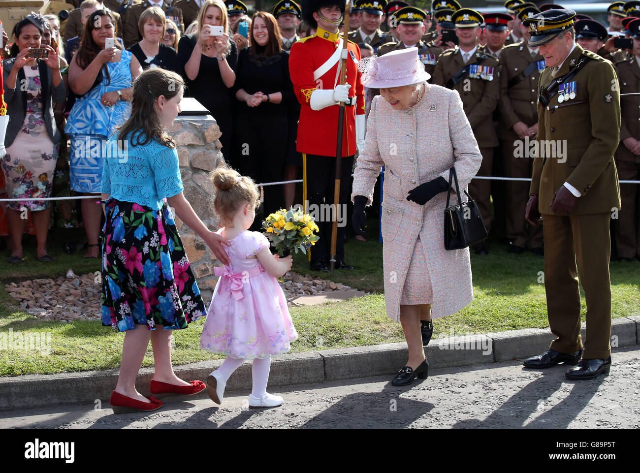 Two year old Heather Leek is ushered forward to give Queen Elizabeth II ...