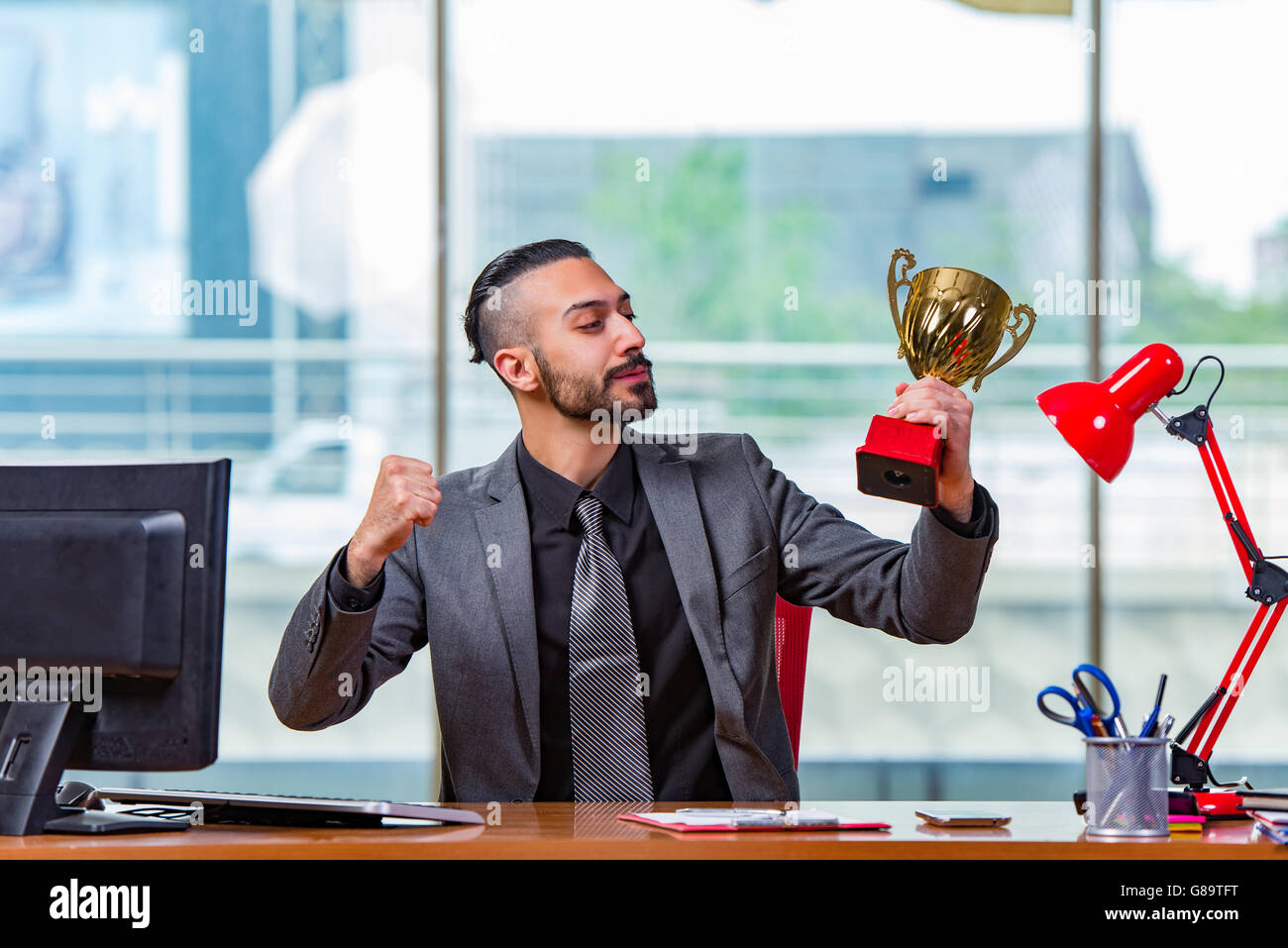 Businessman winning cup trophy in the office Stock Photo - Alamy