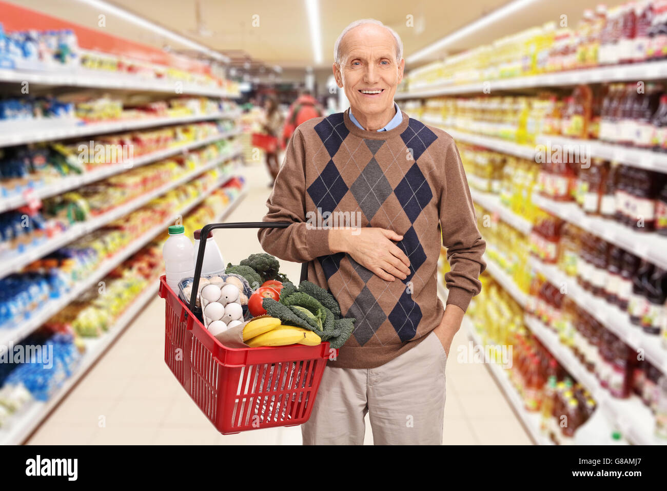 Senior shopping and posing in a supermarket with a basket full of ...