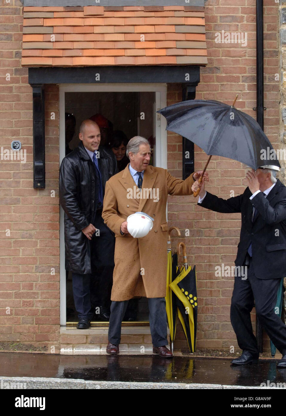 The Prince of Wales is handed an umbrella as he visits Poundbury, to ...