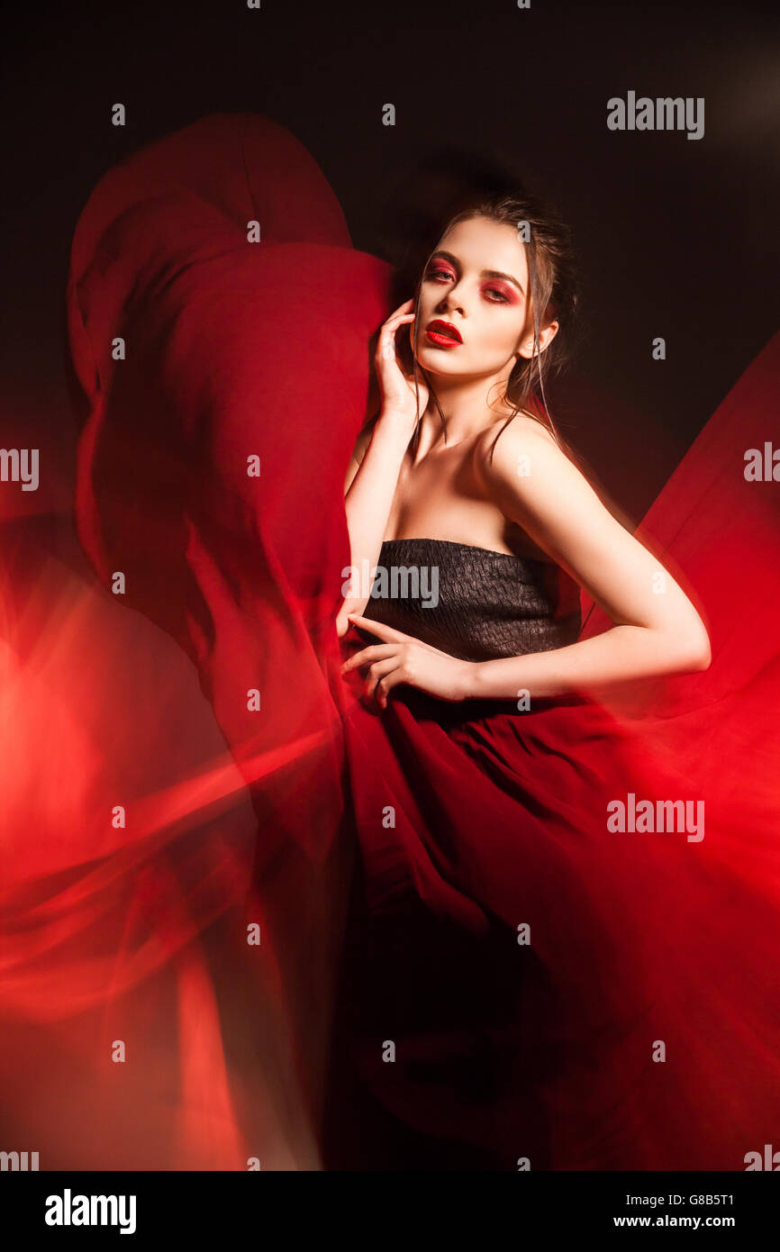 Portrait of sensual attractive model with make-up in waving red dress ...