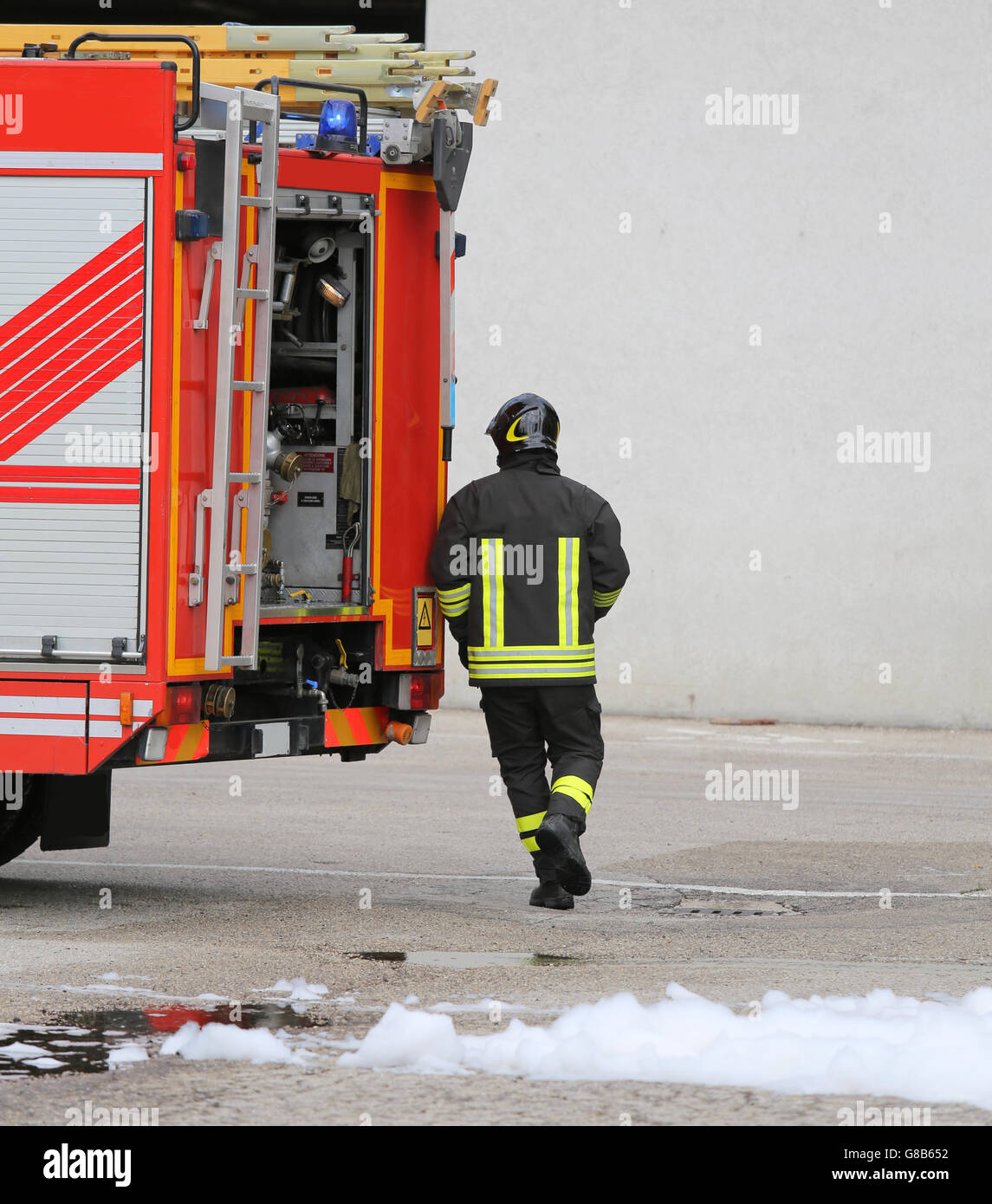 Firefighters running and the red fire engine Stock Photo - Alamy