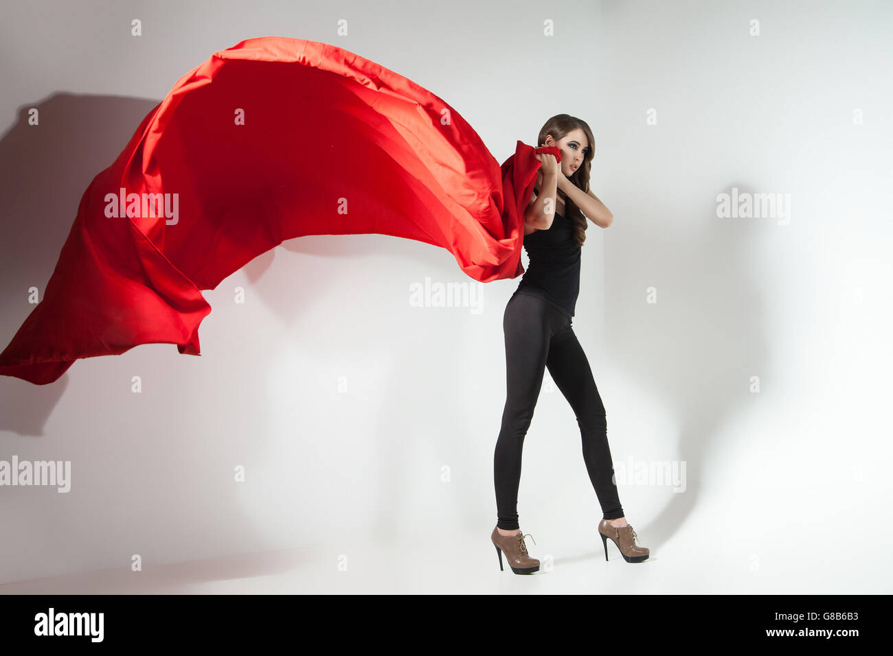 Young girl in black with waving red cloth on white background Stock ...