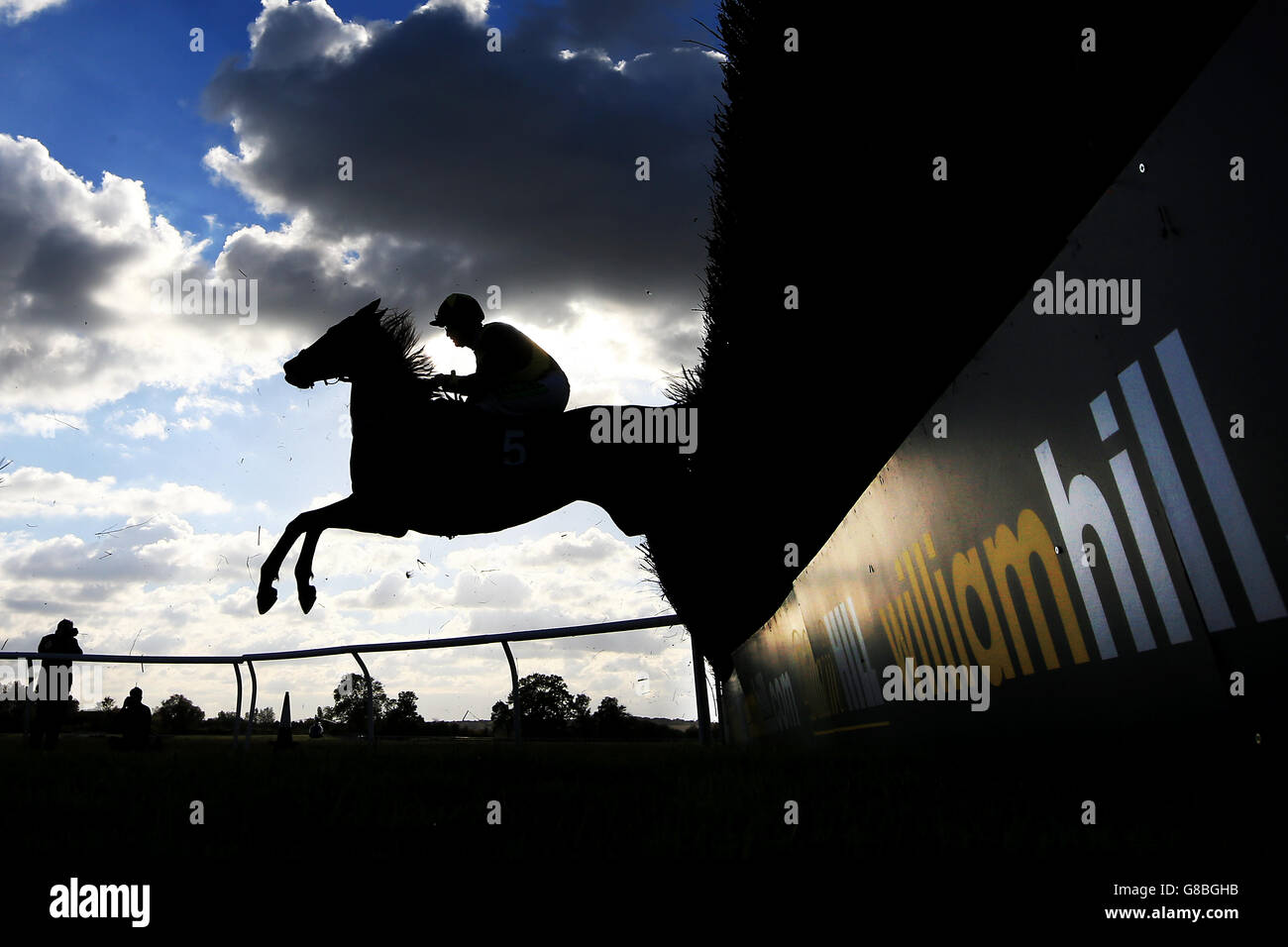 A silhouette of a jockey and horse jumping a fence during the ...