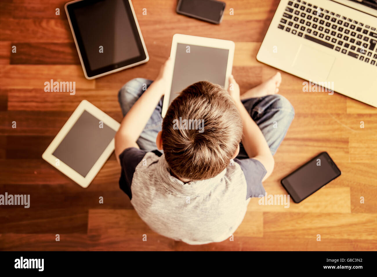 Little boy using tablet PC sitting on wooden floor. Digital tablets ...