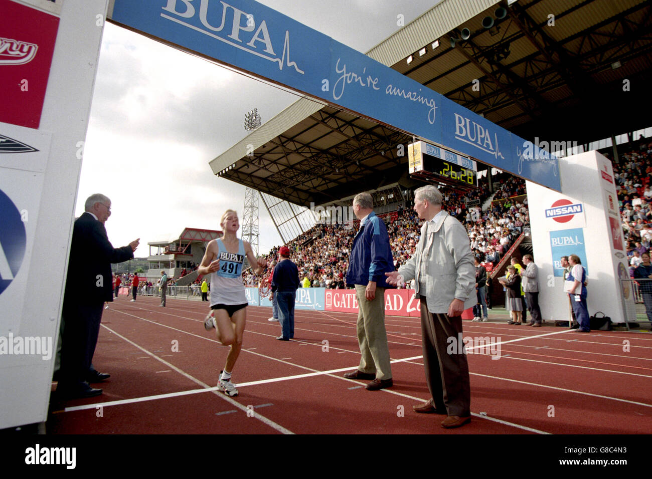 A runner crosses the finishing line in the Gateshead Athletics Stadium ...