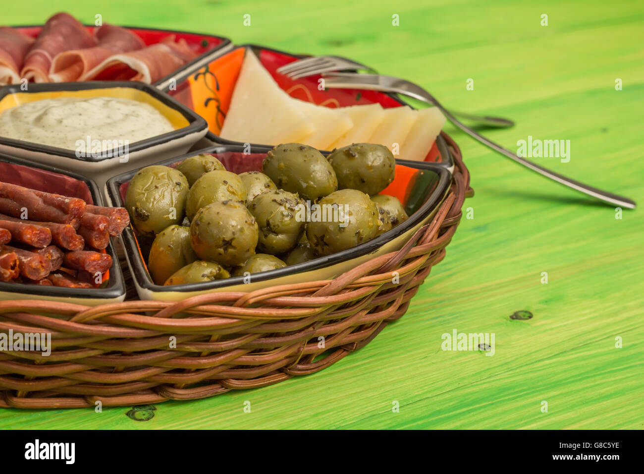 Basket with Spanish tapas on a rustic green wooden table Stock Photo ...