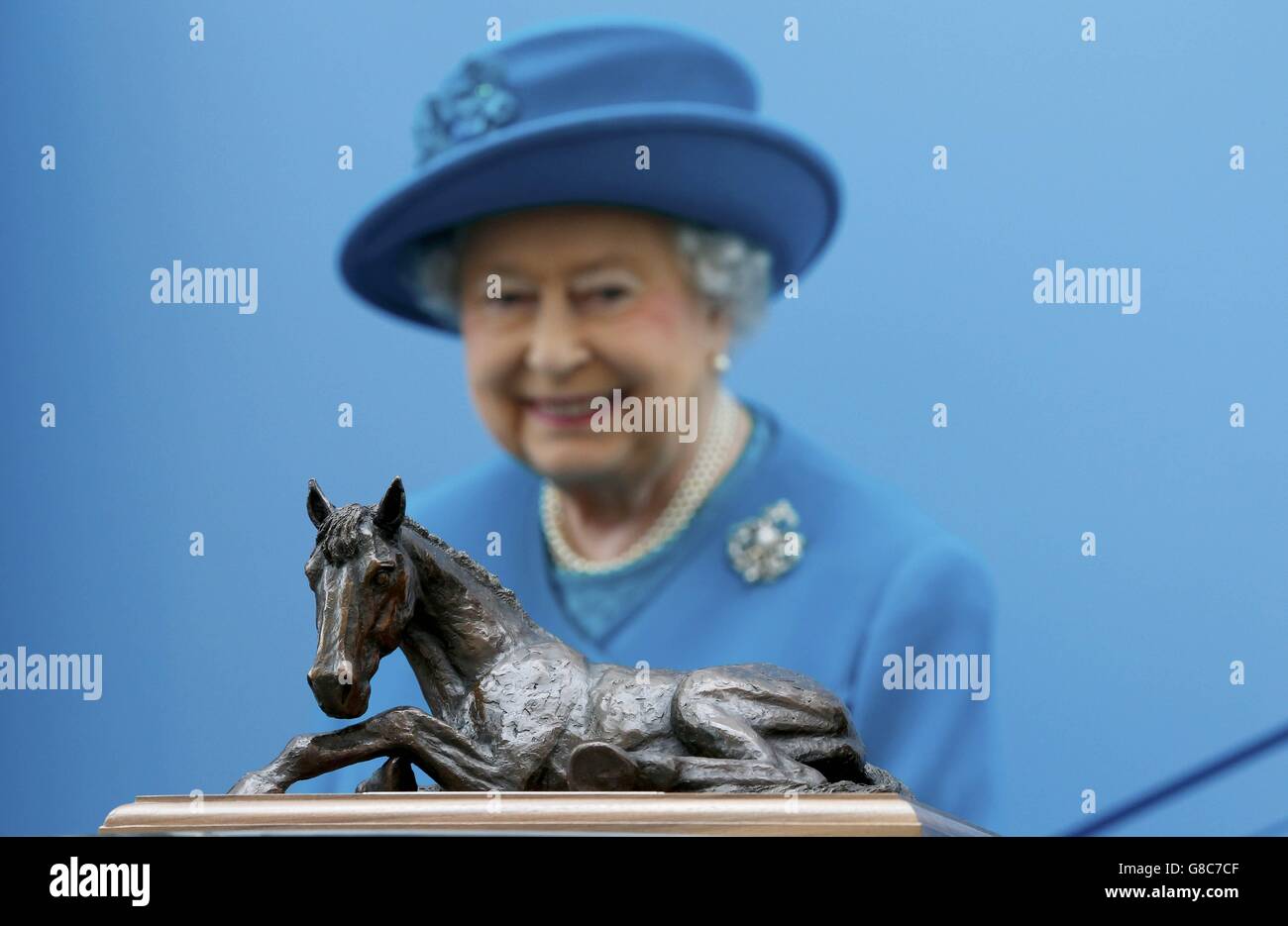 Queen Elizabeth II looks at a bronze statue of a horse that she was ...