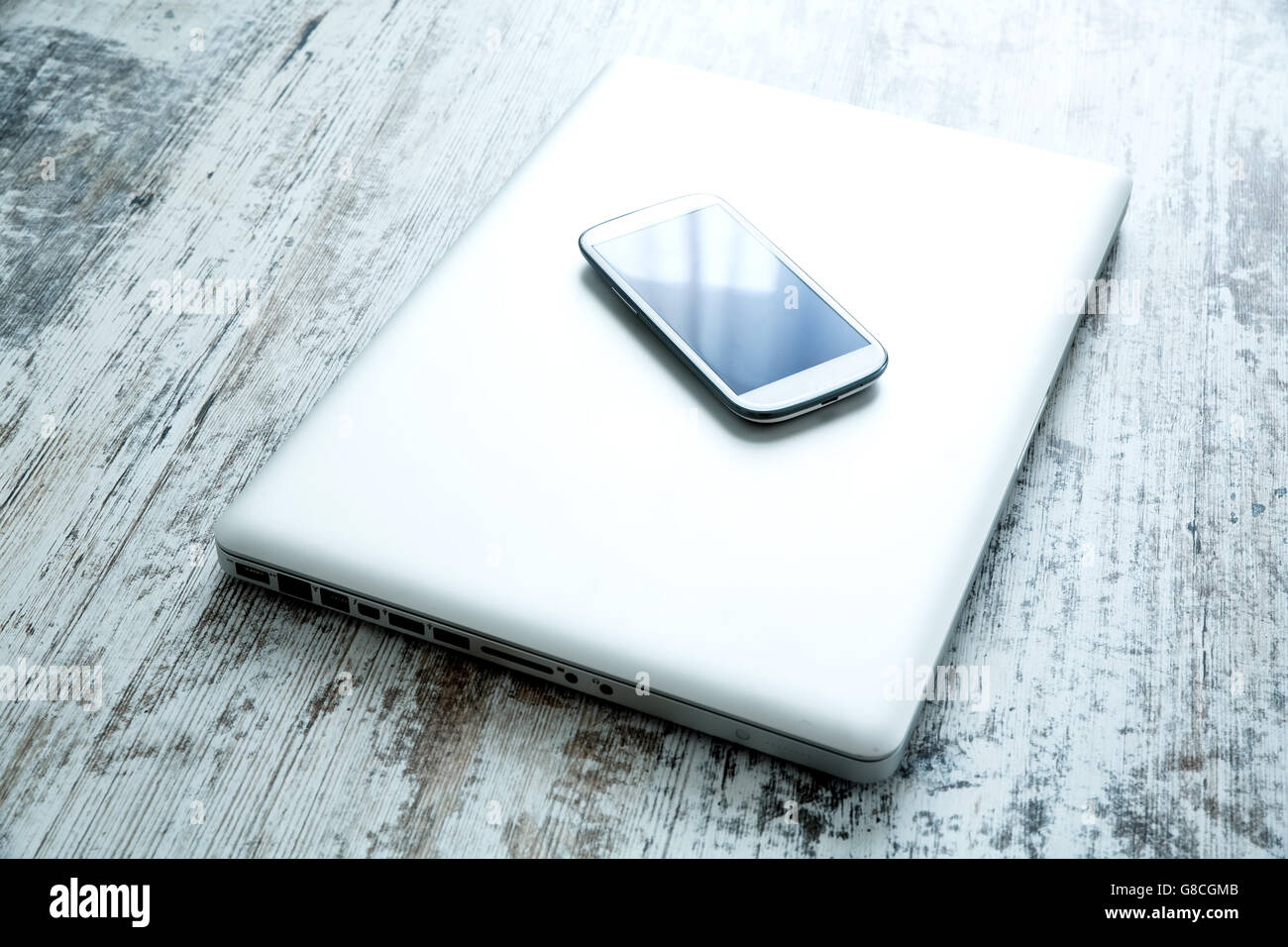 A Smartphone and a switched off laptop computer on a wooden Desktop ...
