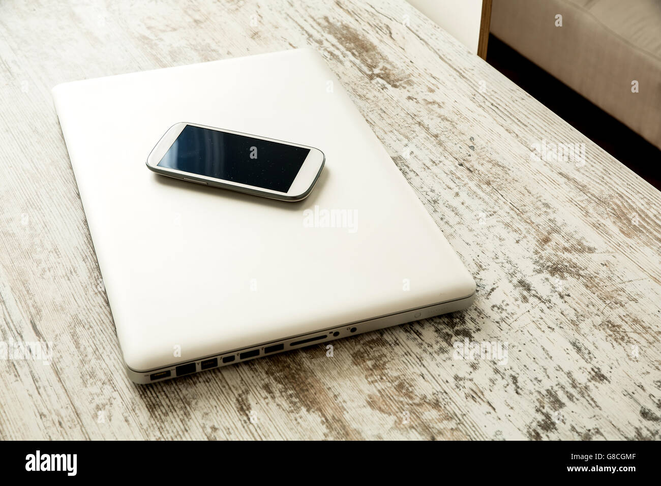 A Smartphone and a switched off laptop computer on a wooden Desktop ...