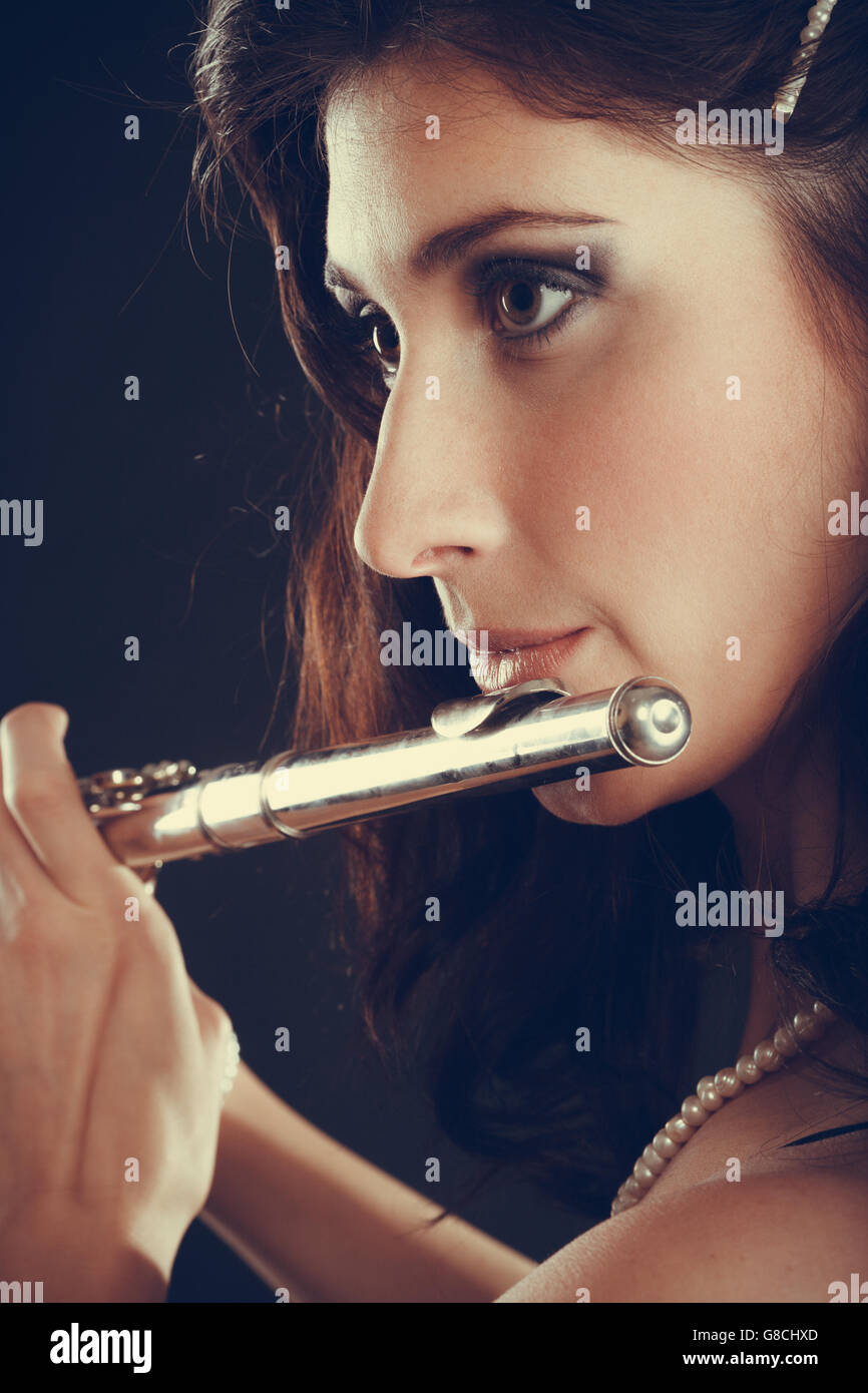 Music and elegance. Alluring elegant woman playing on transverse flute ...