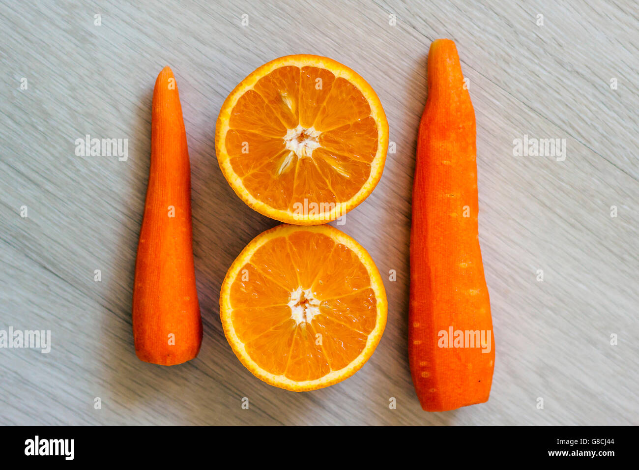 Two halfs of an orange and two carrots on wooden textured background ...