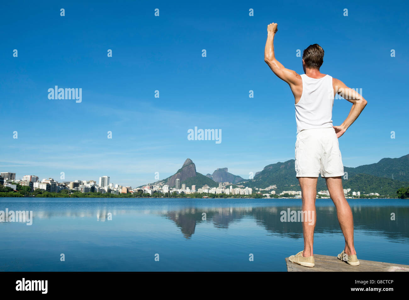 Athlete in white sport uniform standing with champion arms raised in ...