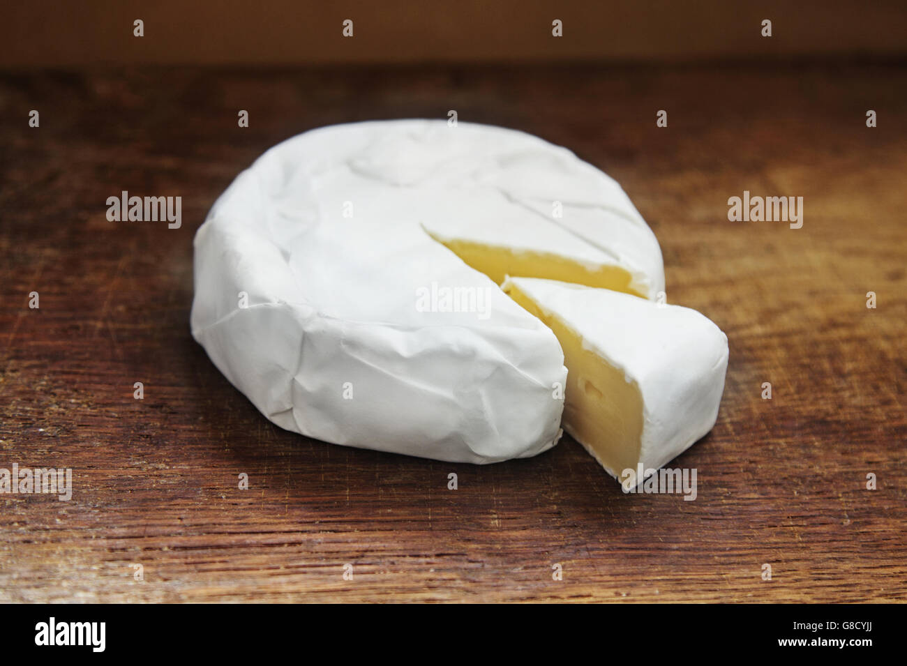 Creamy Brie with cut off piece on rustic wooden background Stock Photo ...