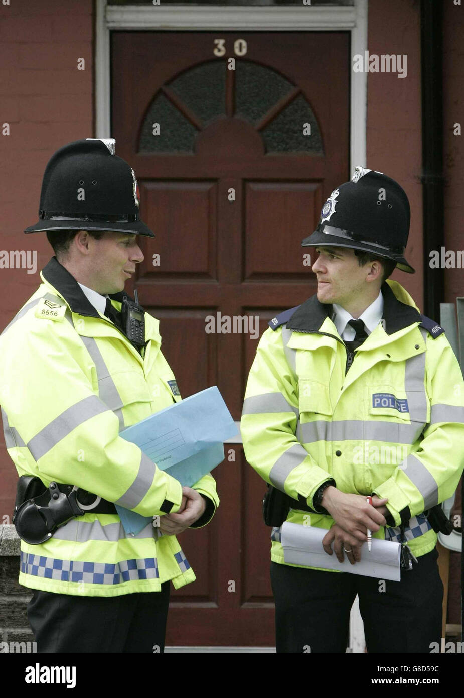 Police officers stand outside the house where a man was arrested during ...