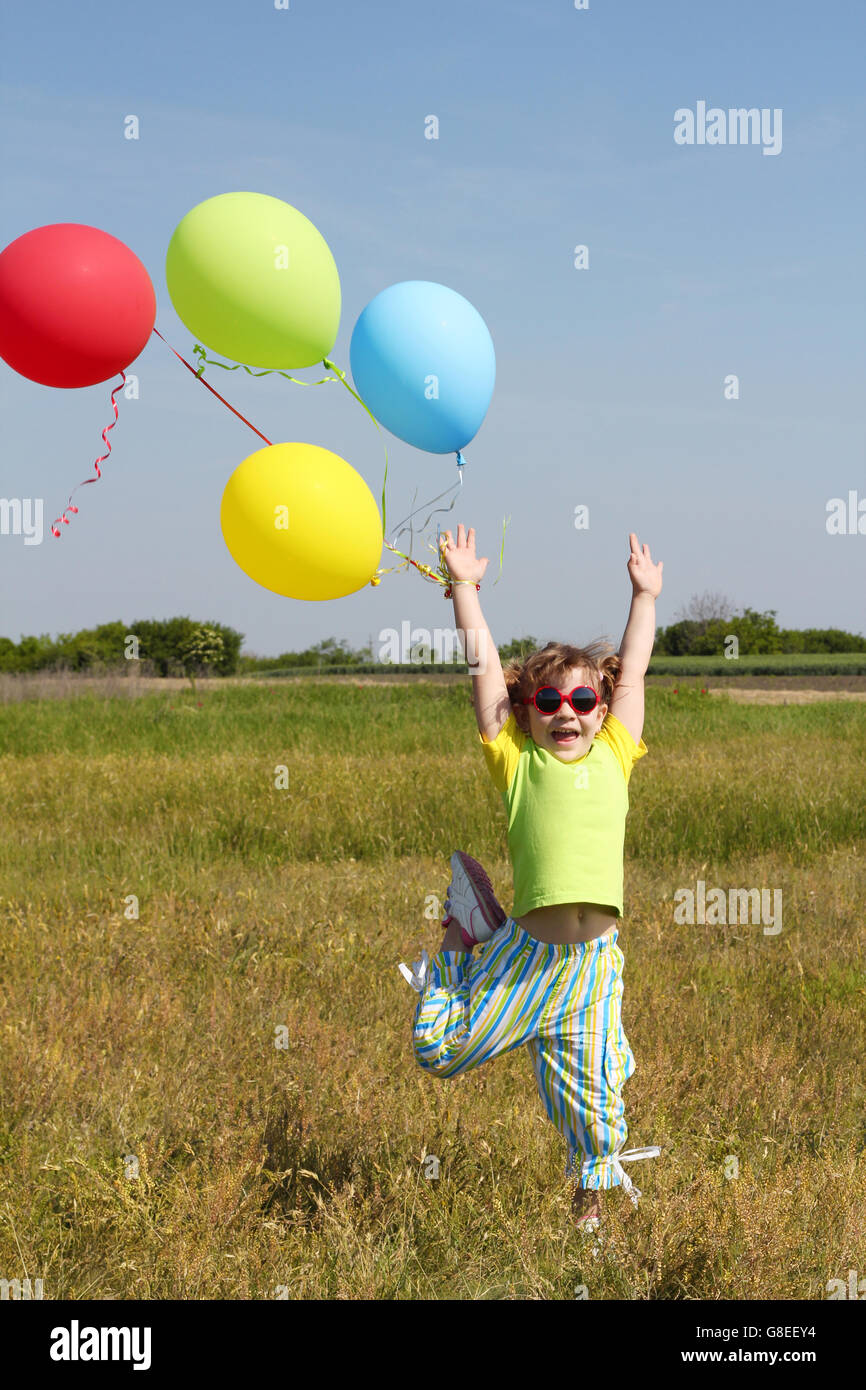 little girl with colorful balloons jumping Stock Photo - Alamy