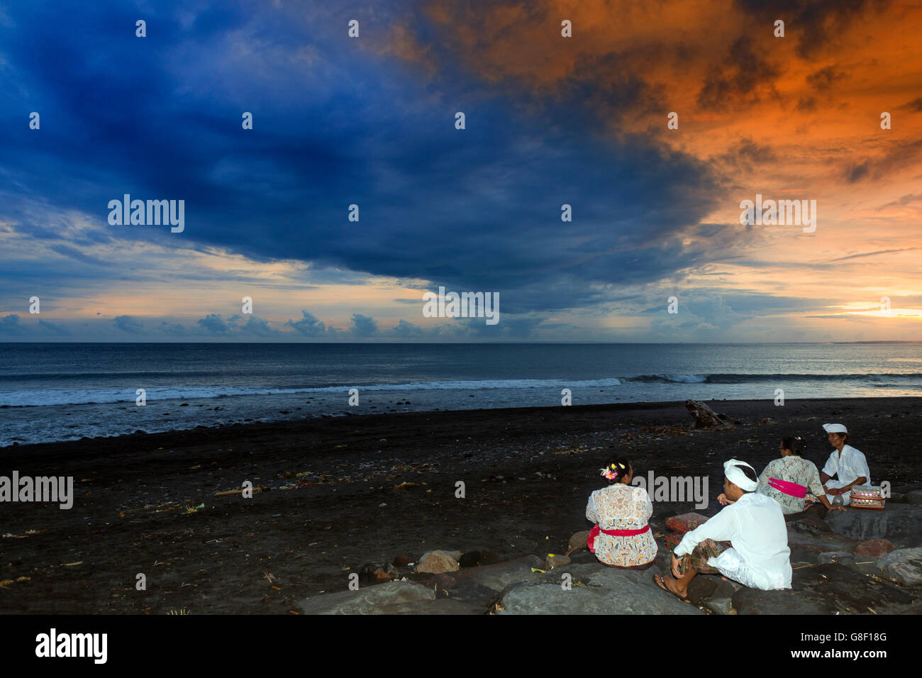Volcanic black sand beach in Bali - temple devotees at sunset Stock ...