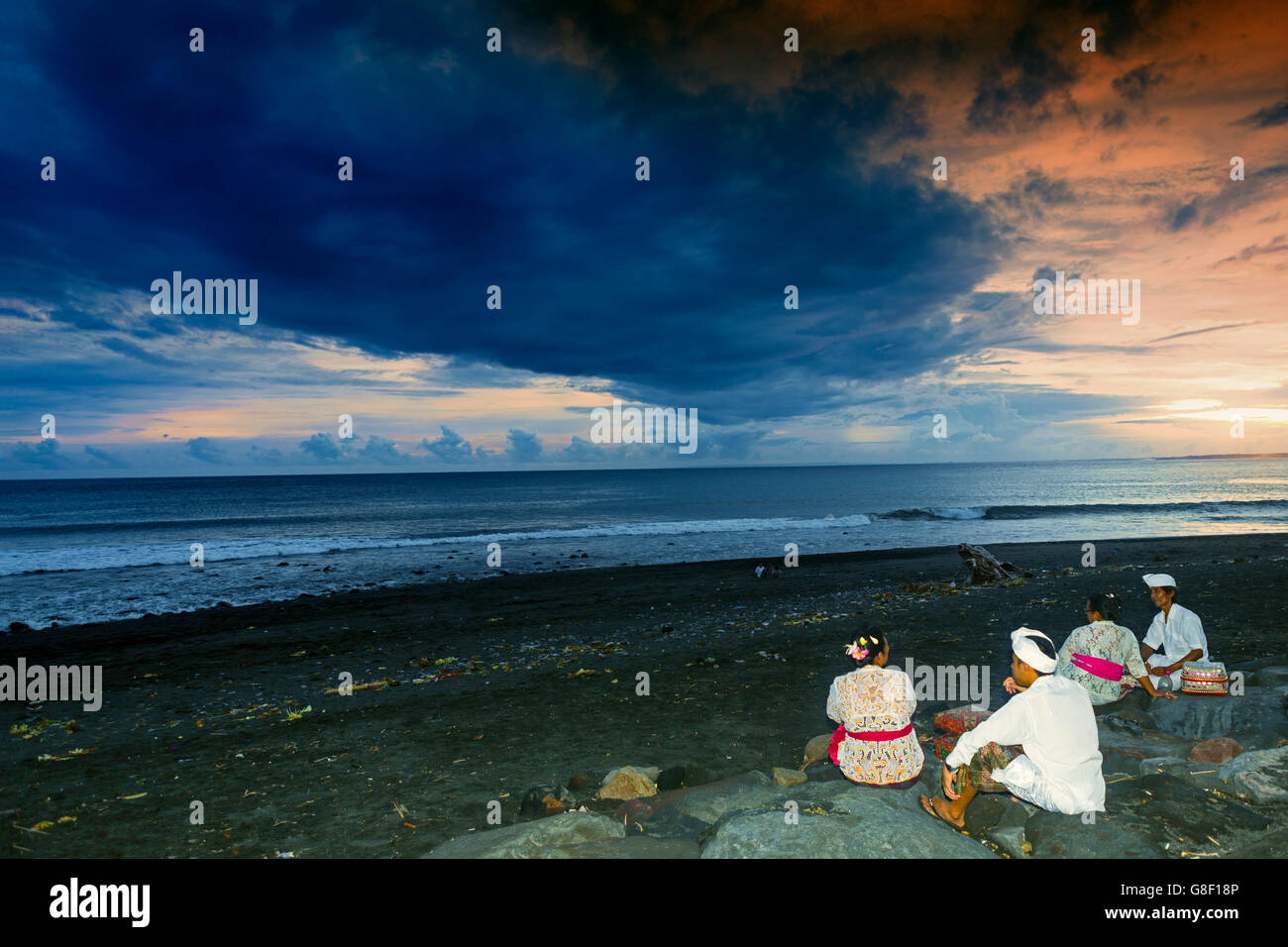 Volcanic black sand beach in Bali - temple devotees at sunset Stock ...