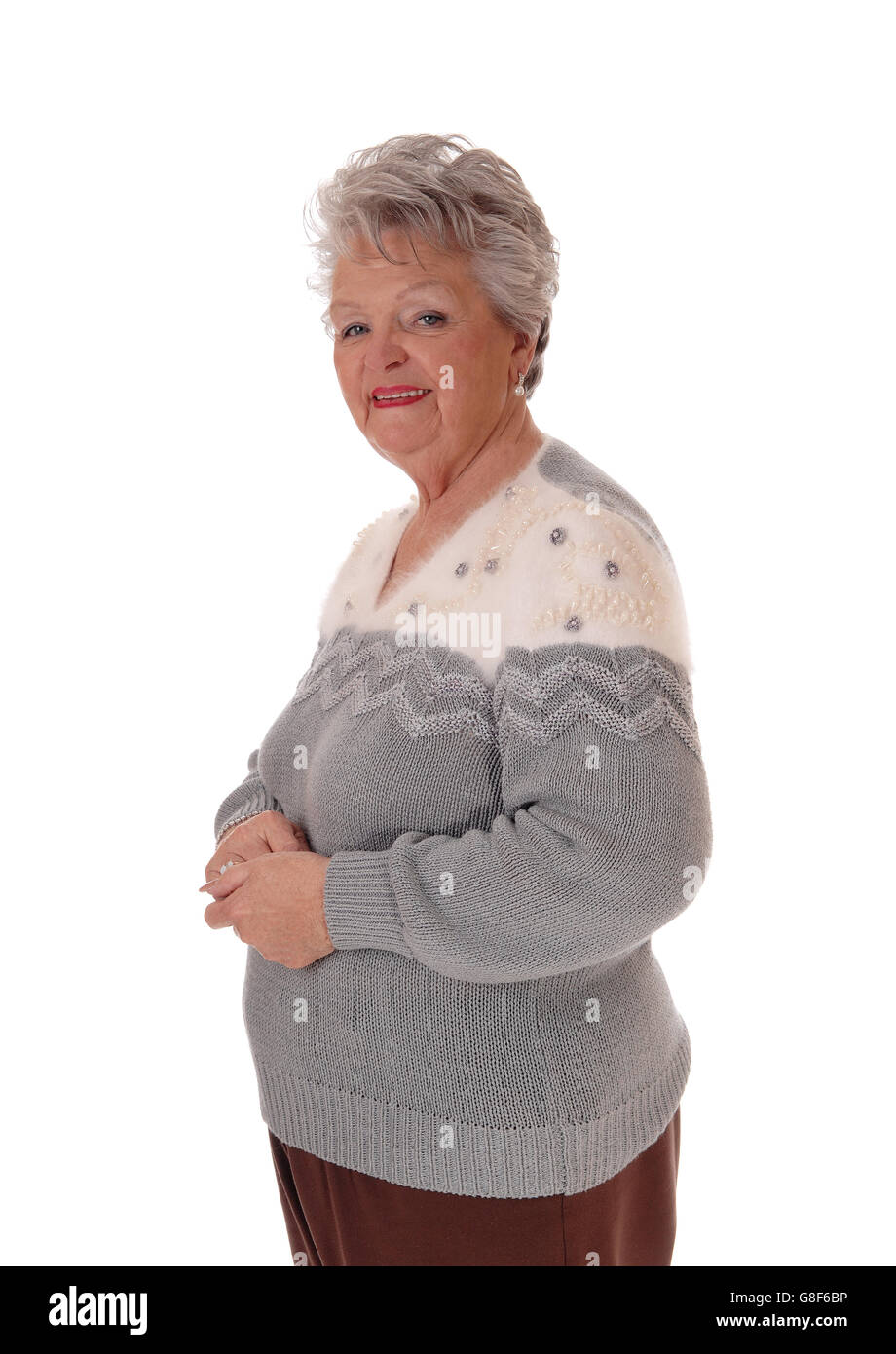 A older senior citizen woman standing in a gray sweater, isolated for ...