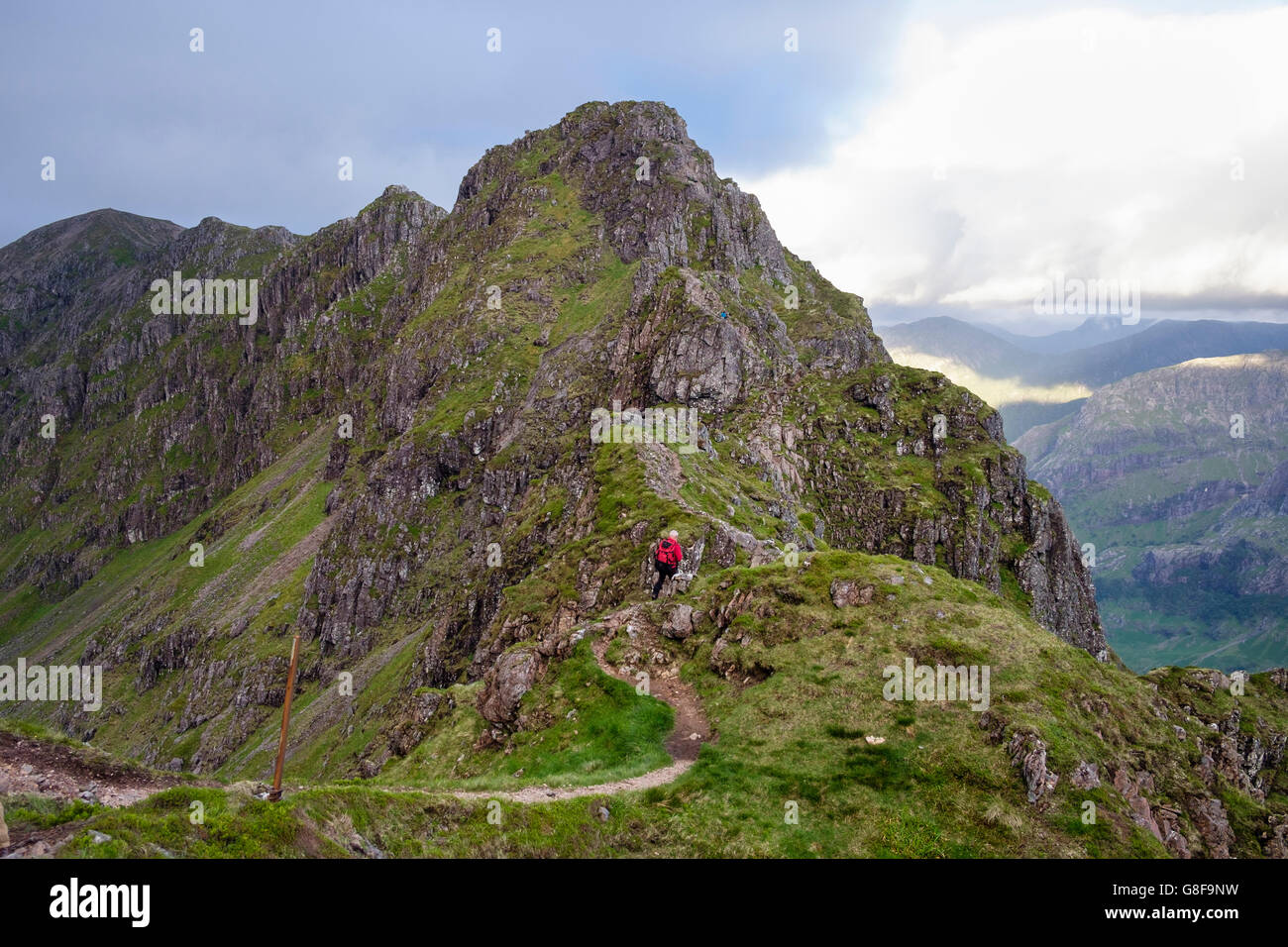 Hiker at western end of Aonach Eagach ridge with view of pinnacles in ...