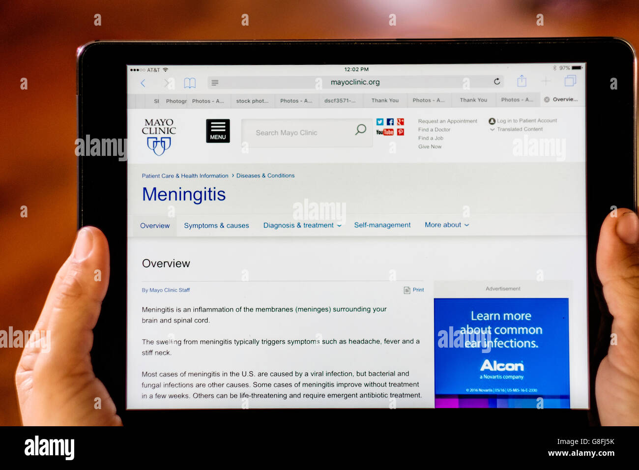 A young woman's hands hold an iPad researching meningitis on the Mayo ...