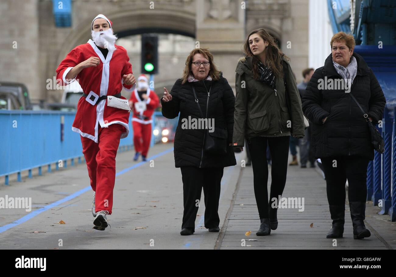 A participant in the London Santa Run, runs across London's Tower ...