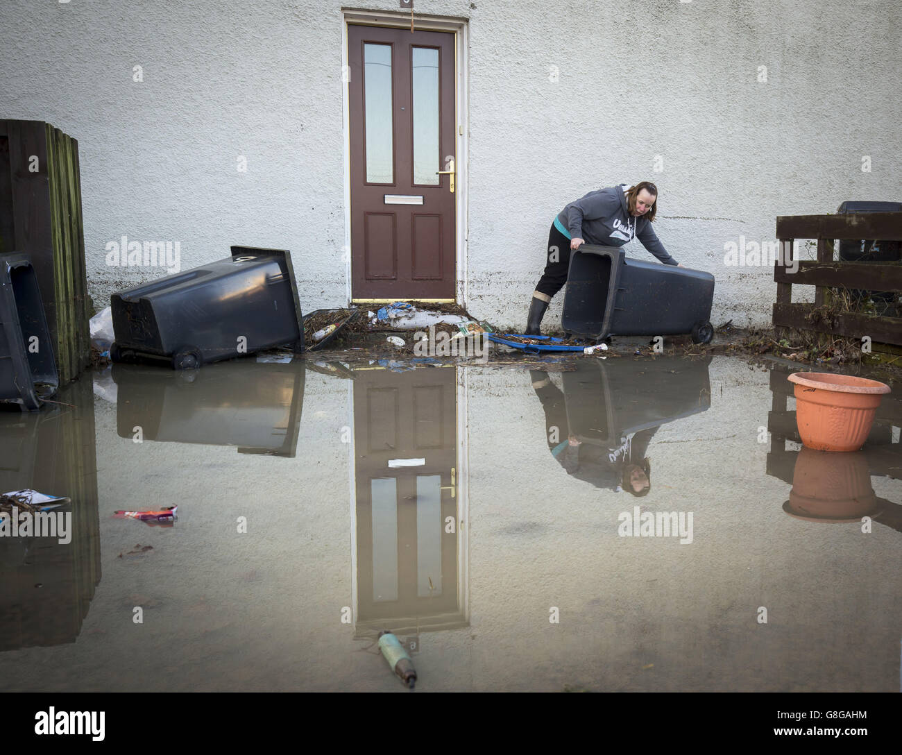 A woman clears flood debris in Hawick, Scotland, after the River Teviot ...