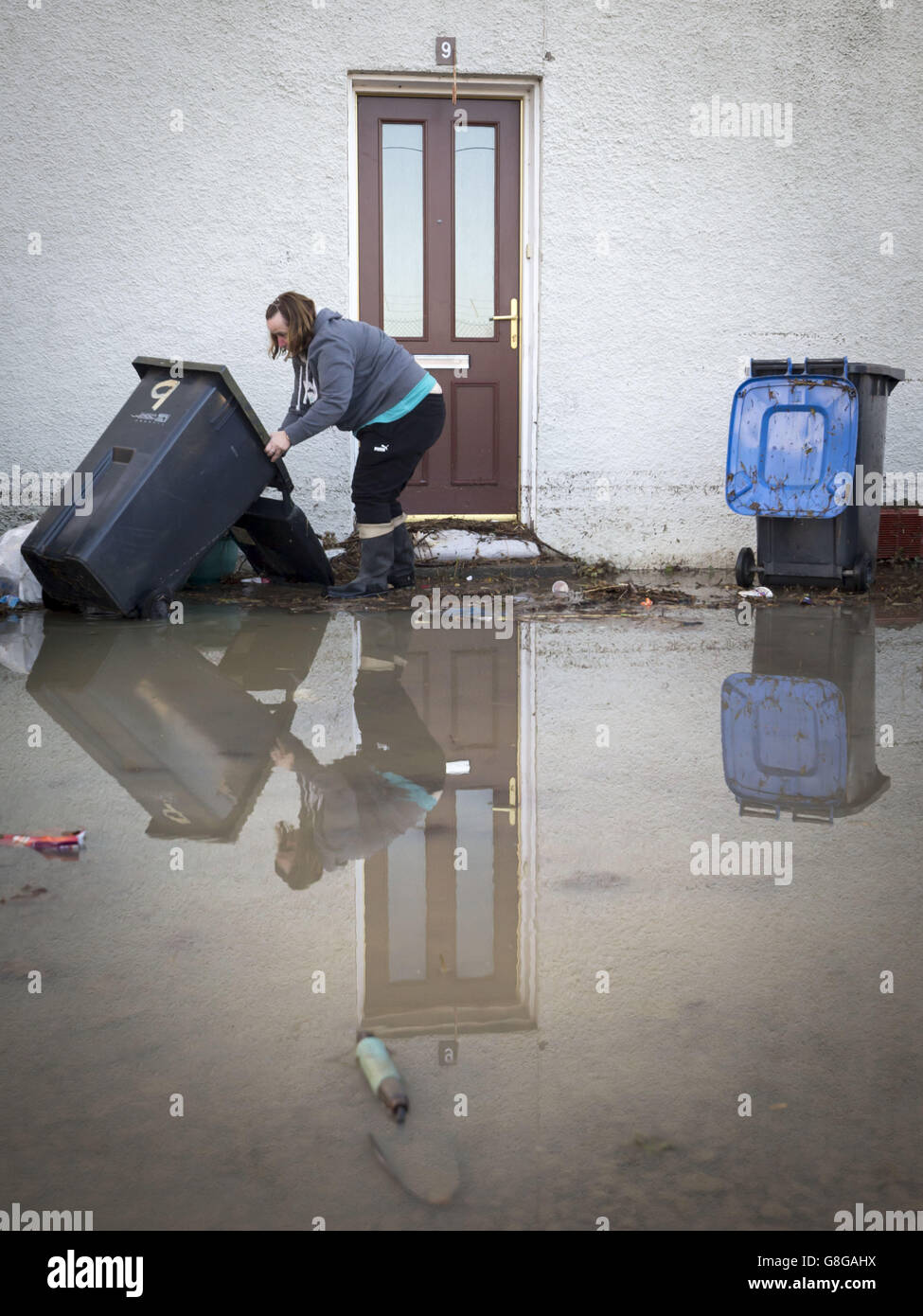 A woman clears flood debris in Hawick, Scotland, after the River Teviot ...