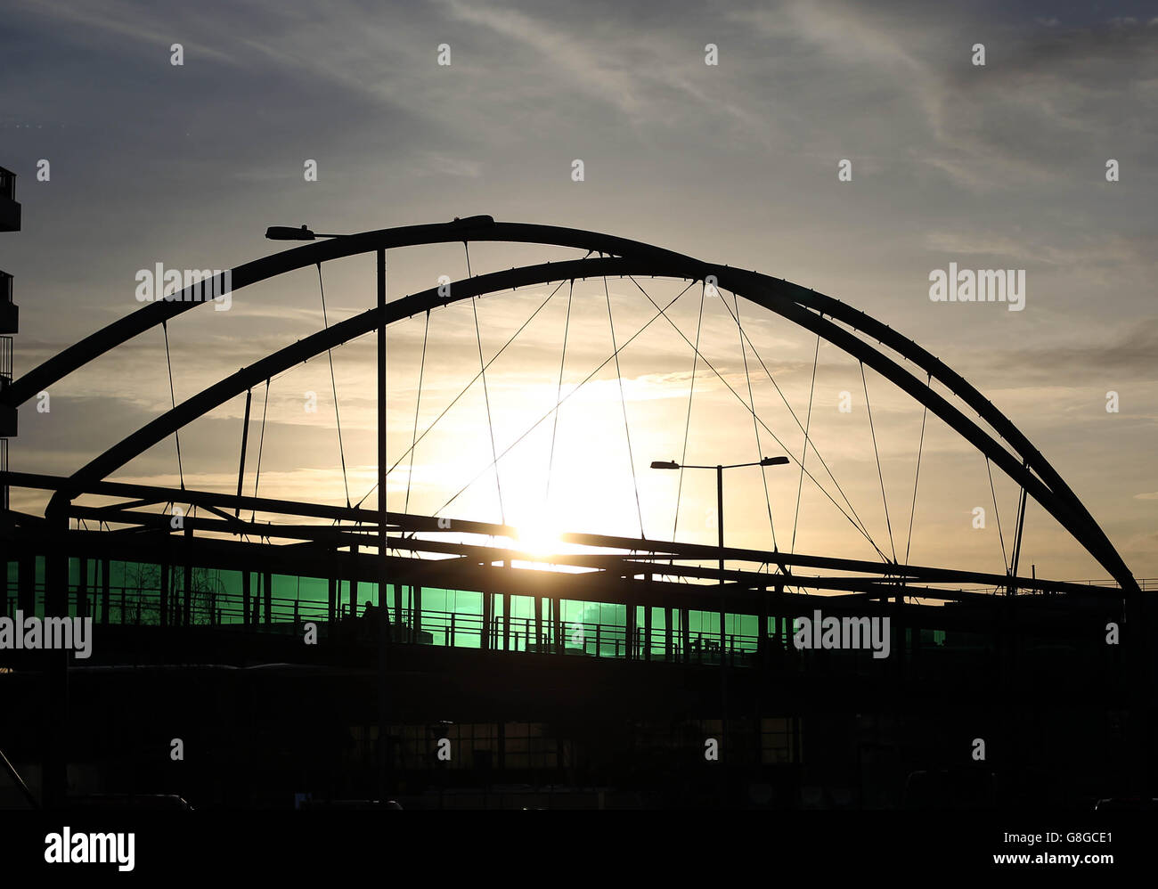 Passengers walk over a footbridge as the sun sets at Terminal 3 of ...