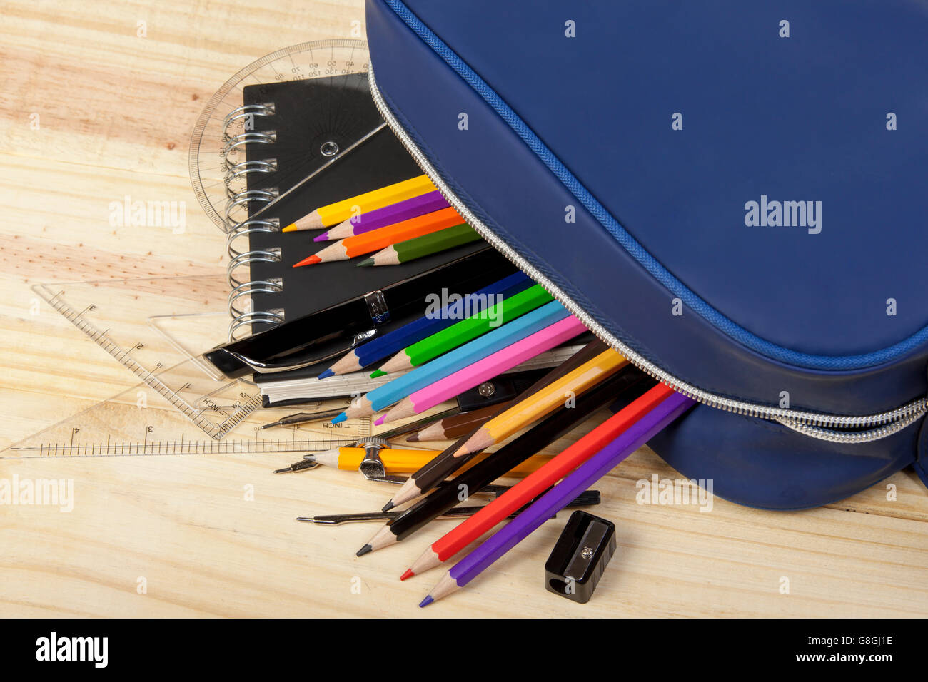 Blue school pencil case spilling it's contents out onto wooden ...