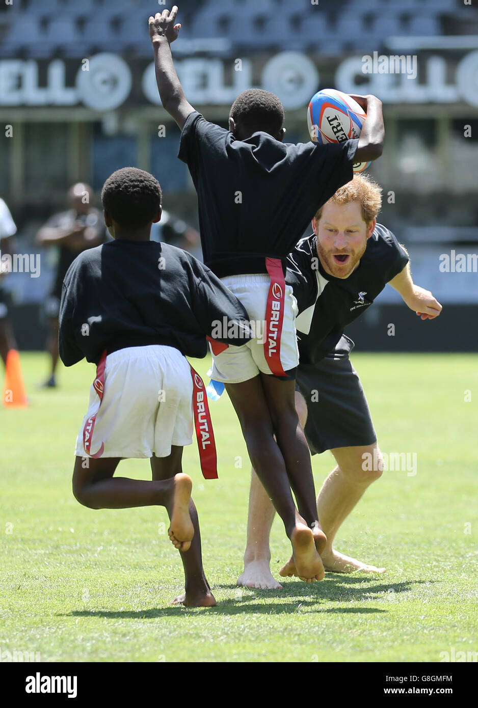 Prince Harry playing tag rugby with children at Kings Park Stadium as ...