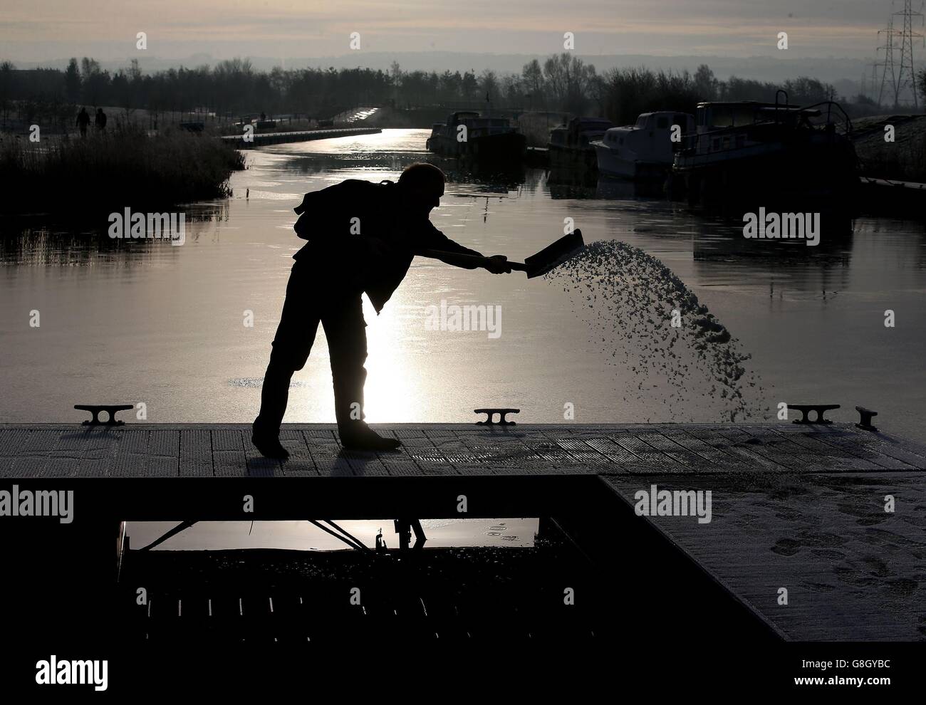 A man spreads grit on pontoons along along the Forth and Clyde canal at ...