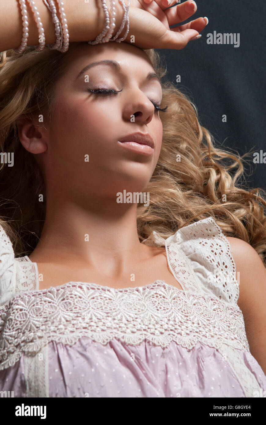 Sad woman laying down hand on head Stock Photo - Alamy
