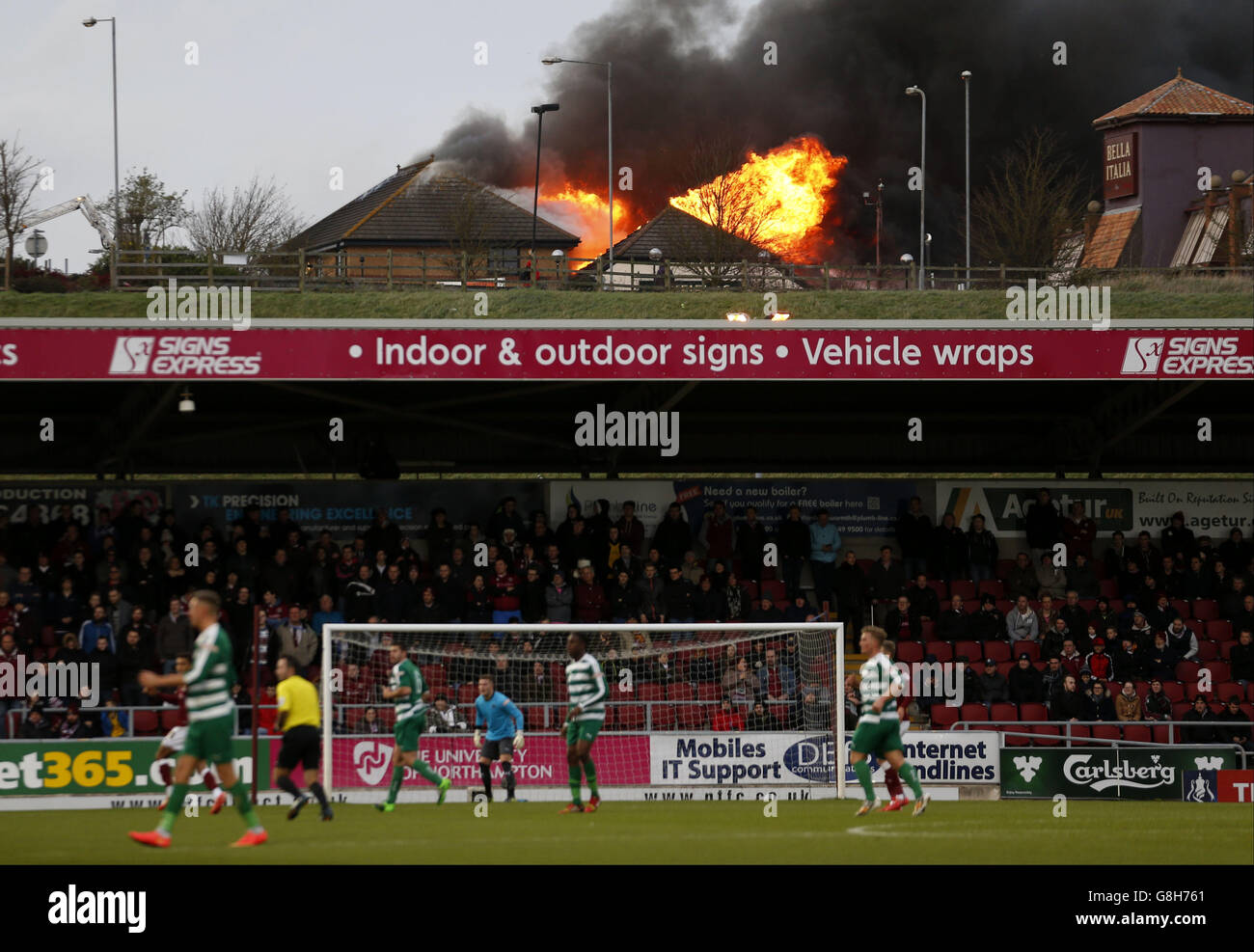 Fire rages at the near by Sixfields Tavern as play continues during the ...