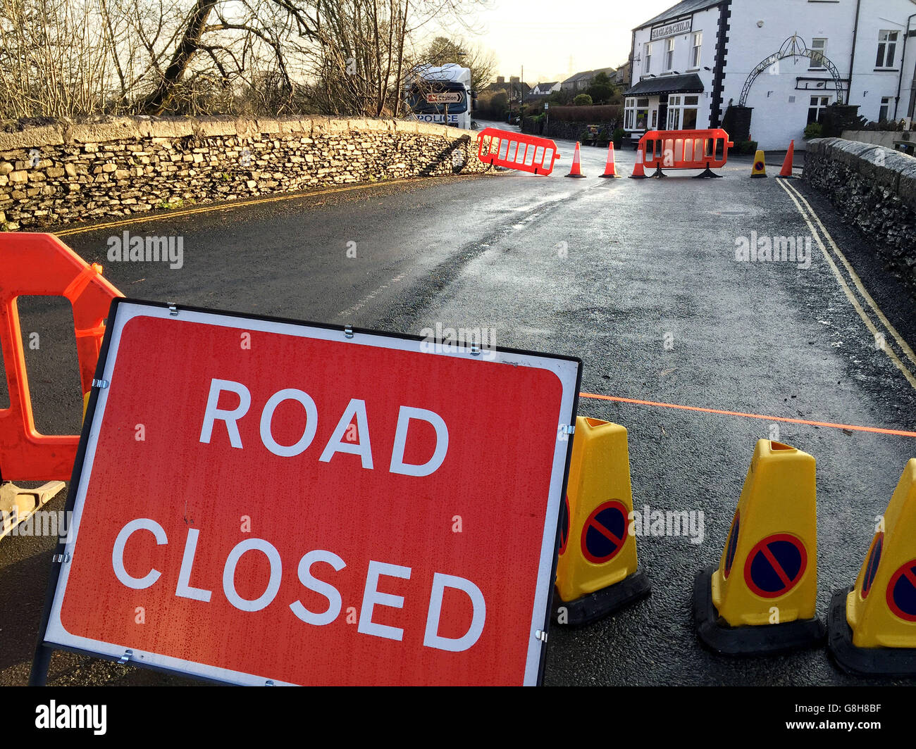 A road closure sign ahead of a bridge over the River Kent on Main ...