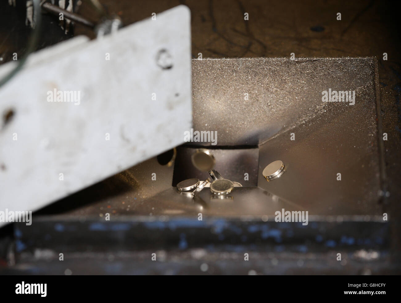 Unminted one pound coins drop down a chute to be struck in the Coin ...